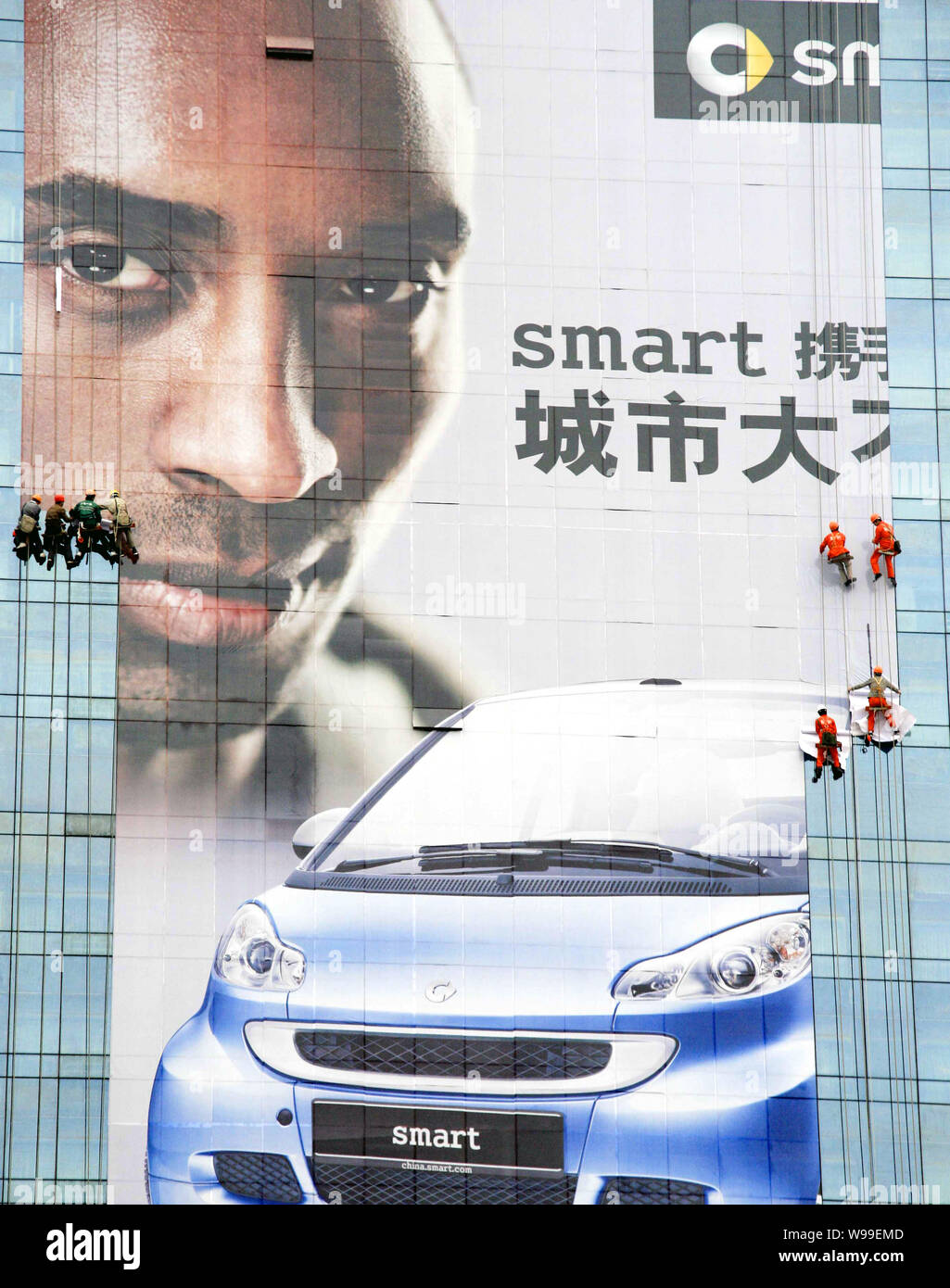Workers hang a huge advertising poster of Kobe Bryant as the brand ...