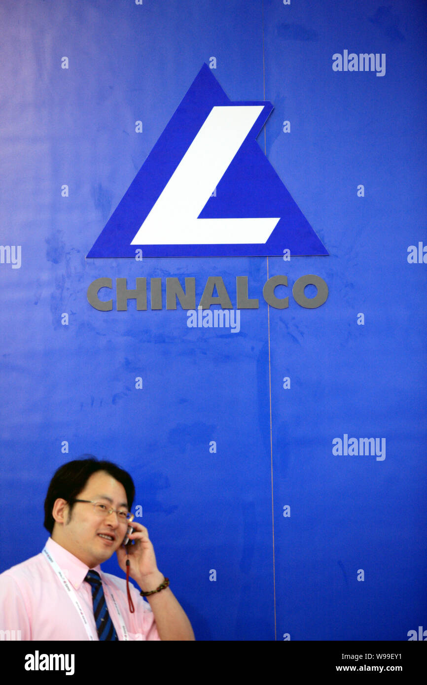 --File-- A Chinese man talks on his mobile phone in front of the logo ...