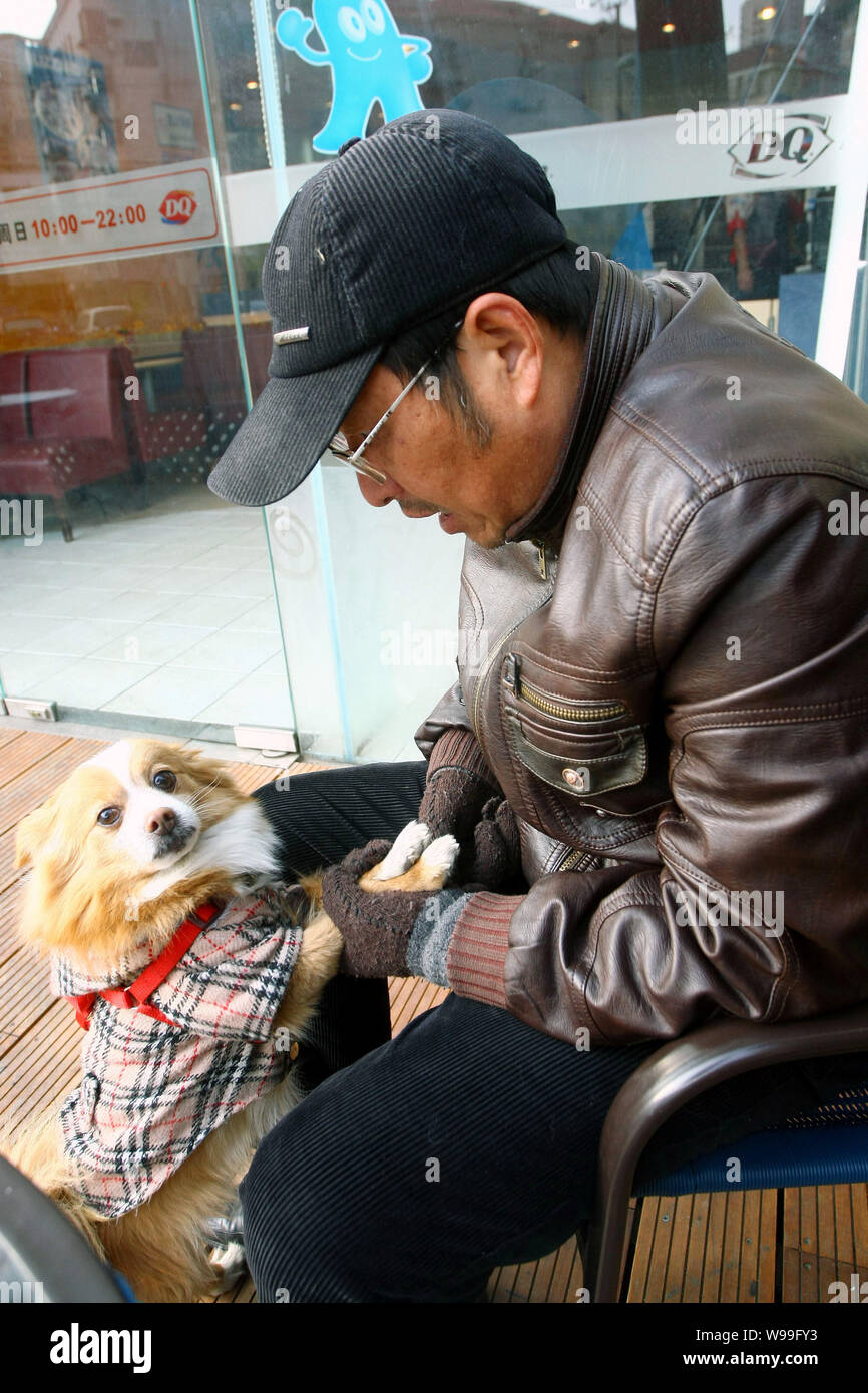 A Chinese man rests with his pet dog on a street in Shanghai, China ...