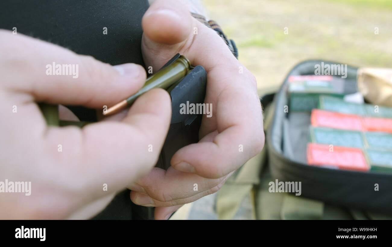 man's hands loading a pistol magazine. man loads the clip of pistol ...