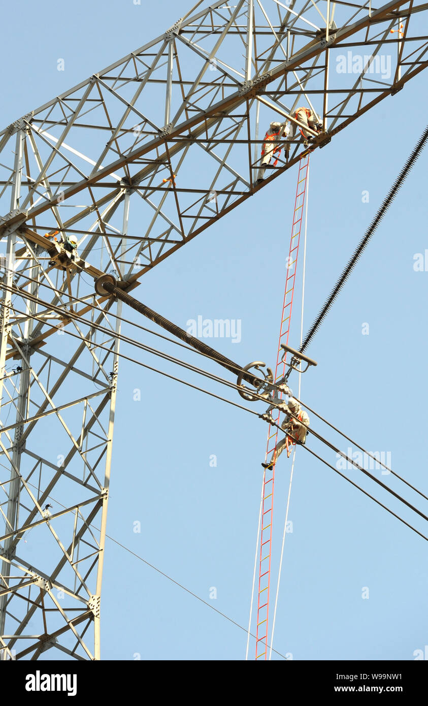 Electricians on a pylon watch another repairing 660kv power lines in ...