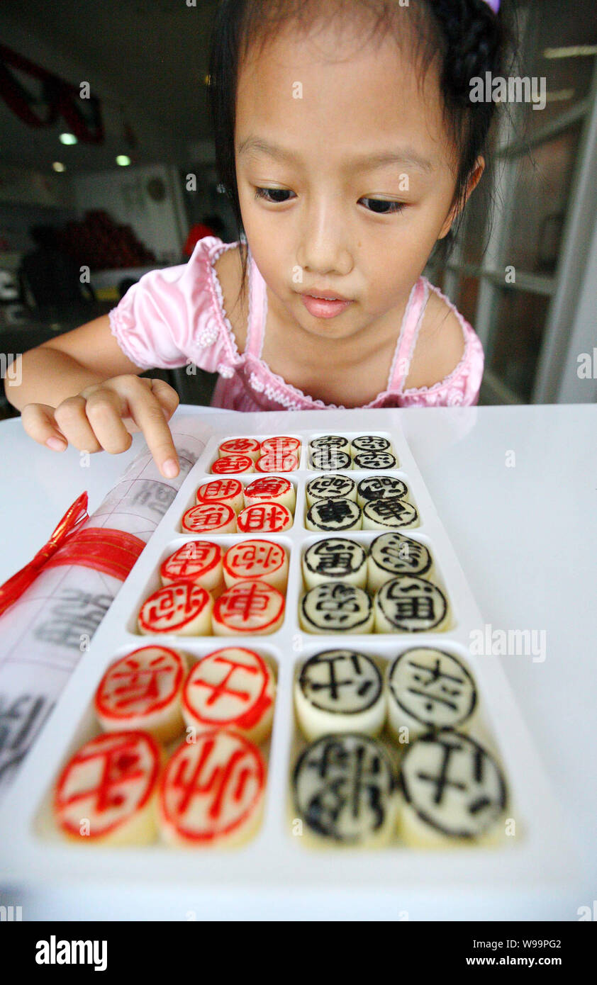 A young Chinese girls looks at chess pieces made from mooncakes at a ...