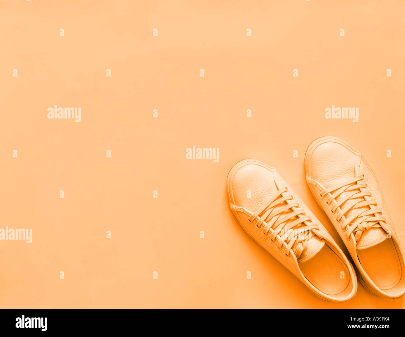 Orange leather sneakers on pastel orange background, monochrome. Pair ...