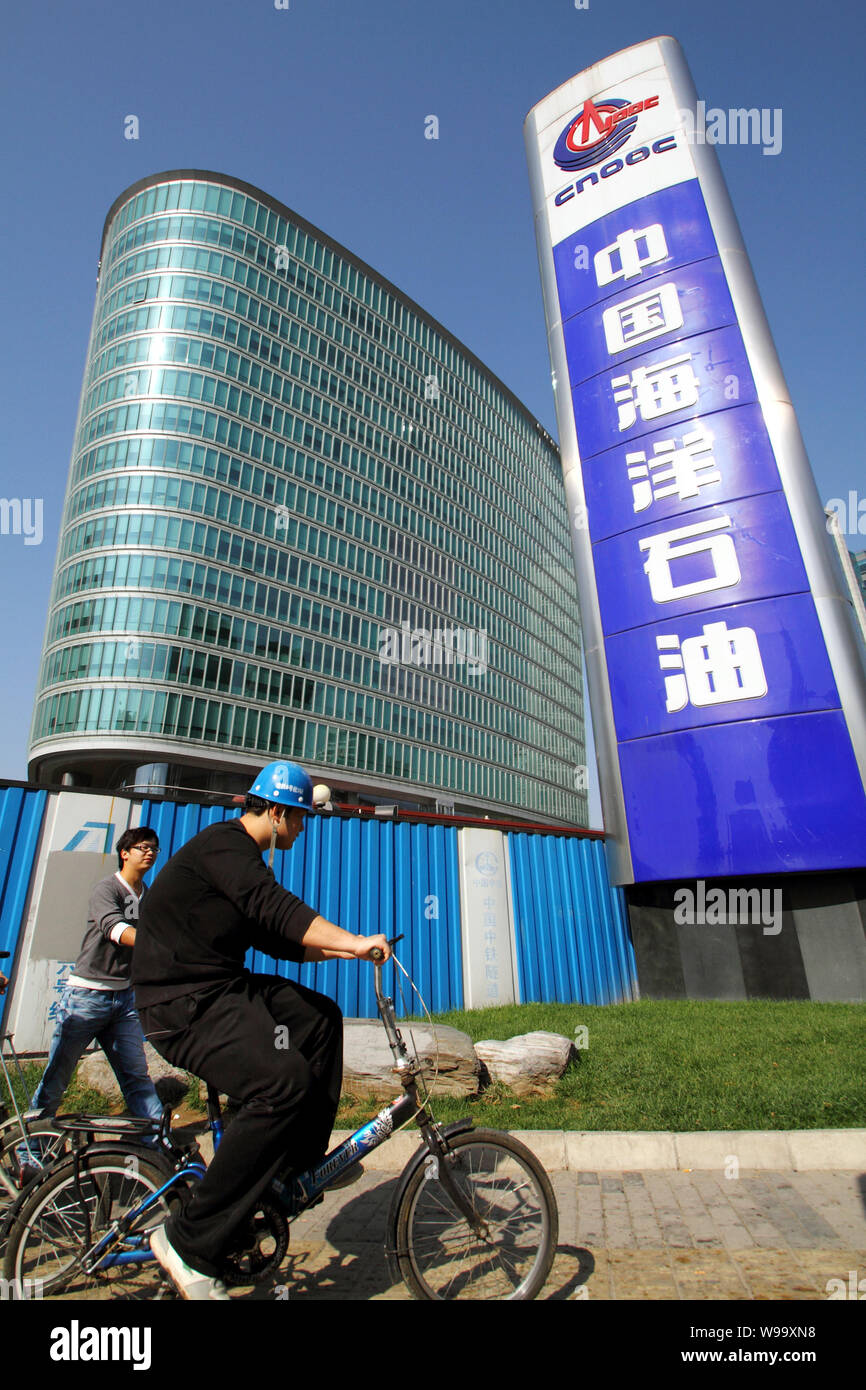 --FILE--Chinese workers pass by the headquarters of CNOOC (China ...