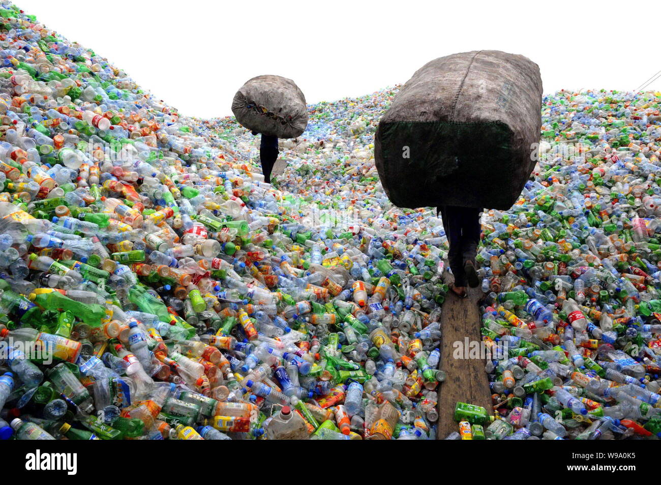 --FILE--Chinese junkmen carrying big bags walk amid piles of waste ...