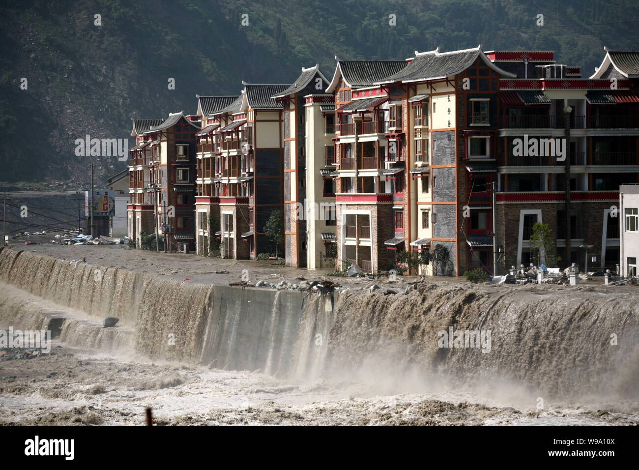 Floodwaters gush past residential buildings after rain-triggered ...
