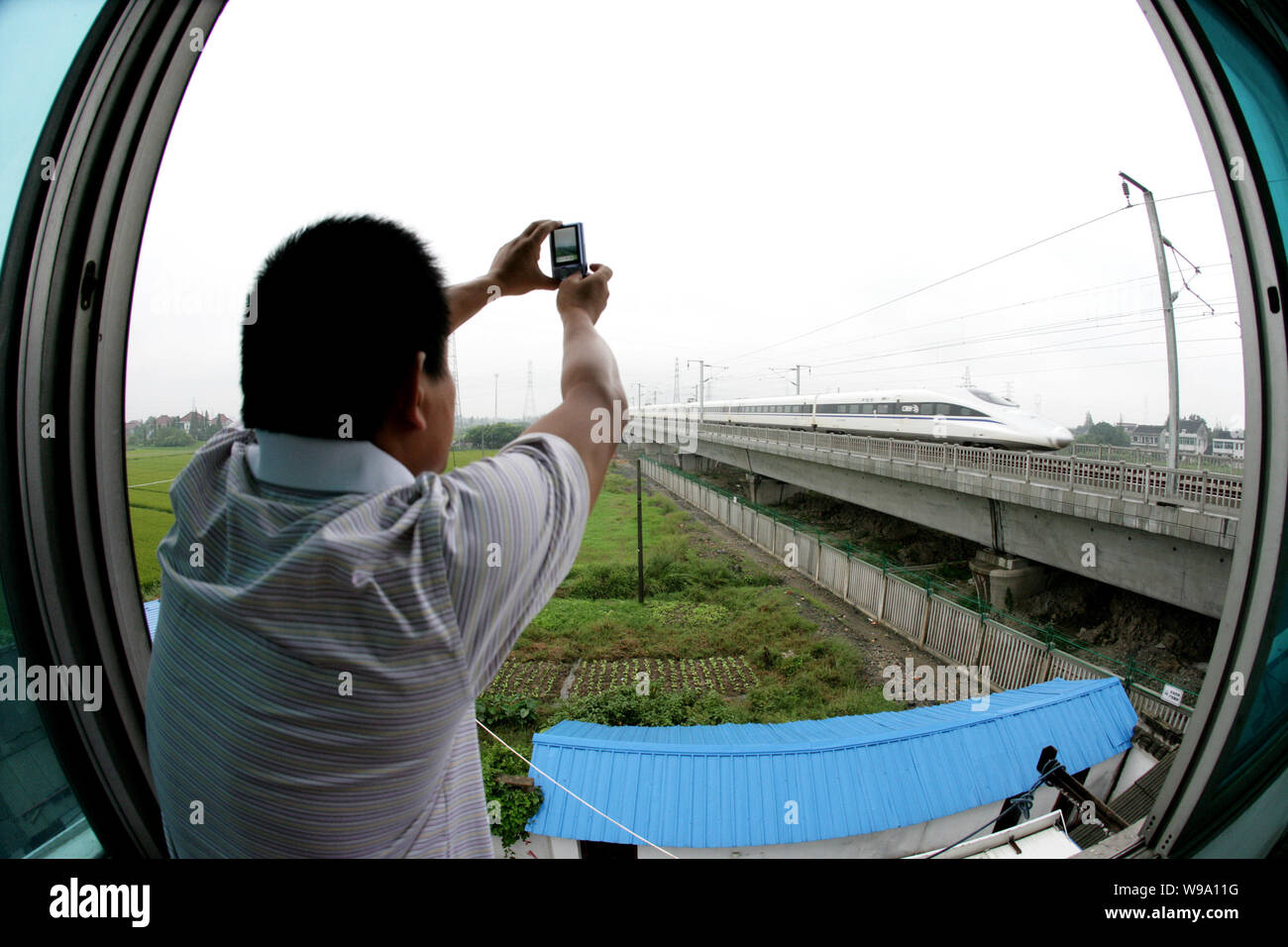 A Chinese man takes photos of a CRH (China Railway High-speed) train ...
