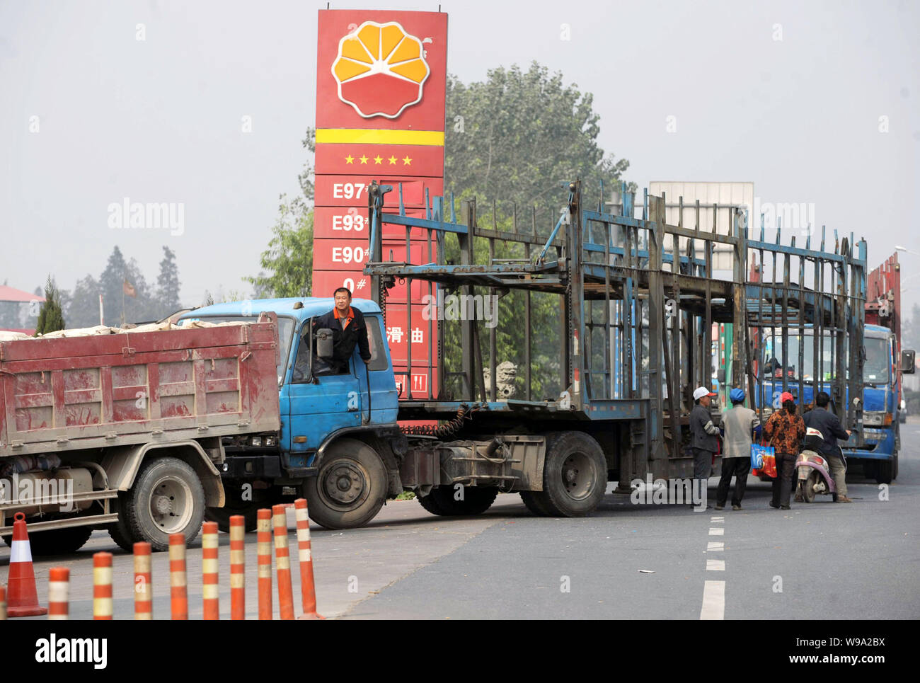 Chinese drivers line up their trucks to be refueled with diesel at a ...