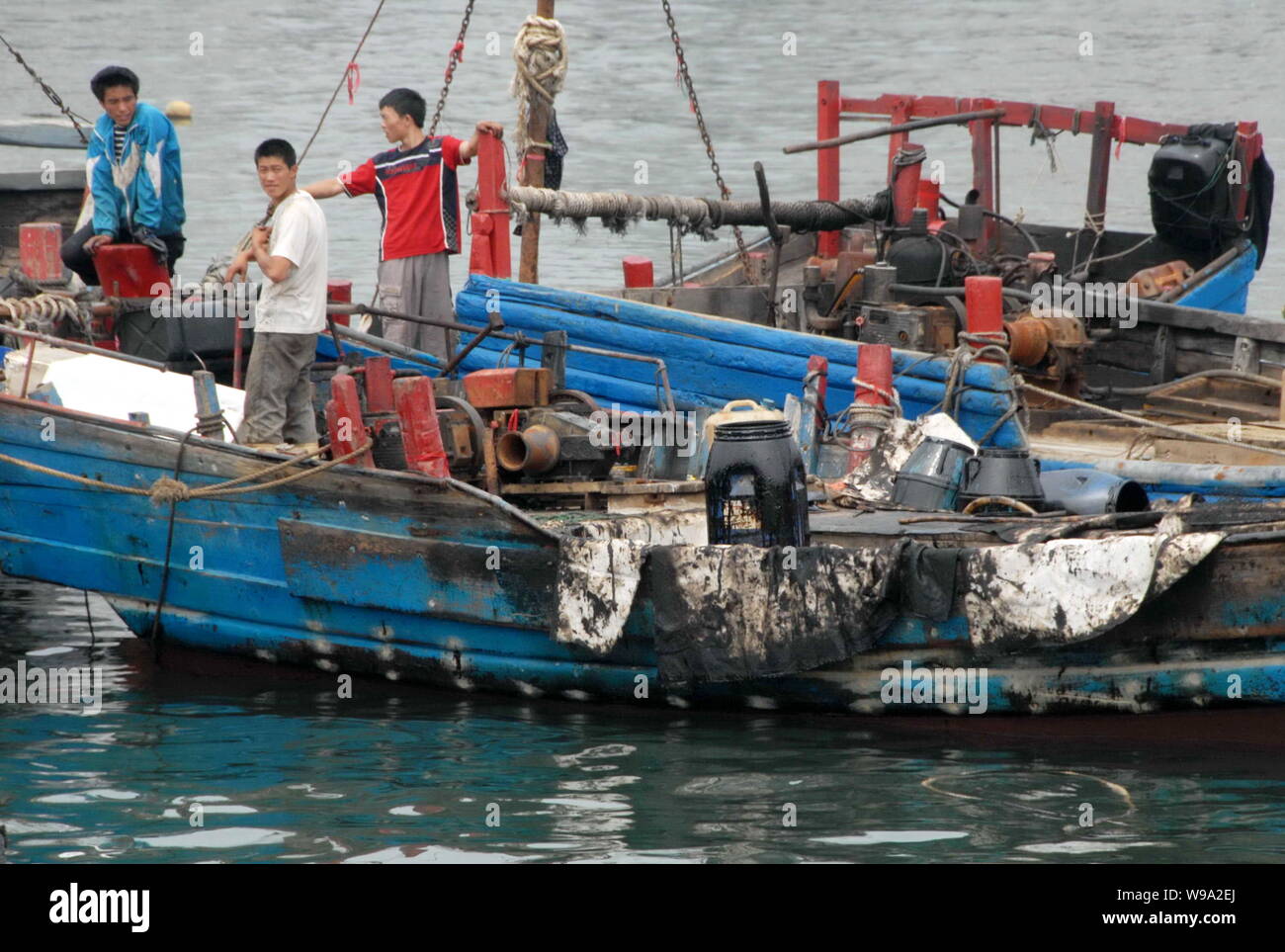 Chinese workers drive fishing boats back to a port after collecting ...