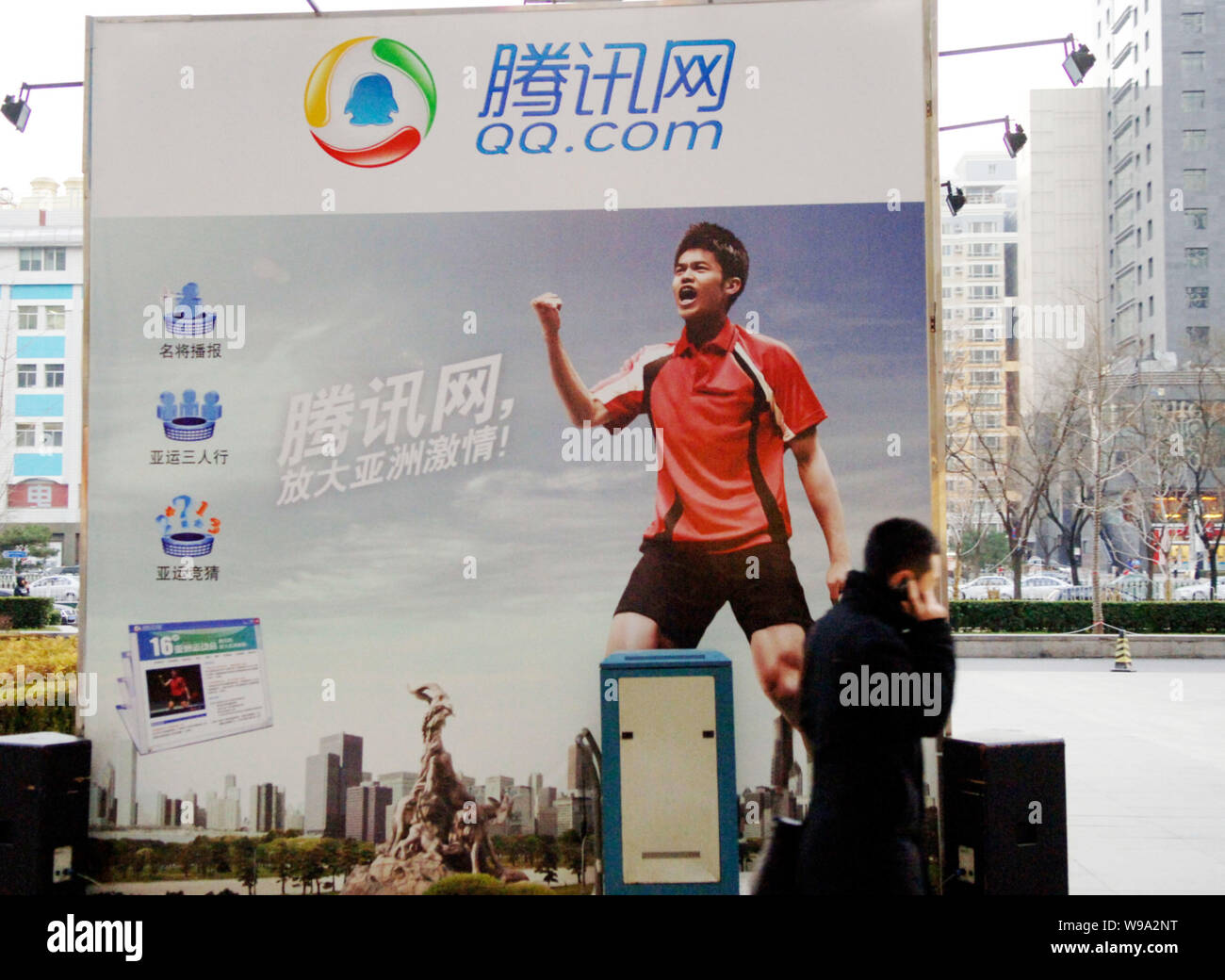 A Chinese man walks past an advertisement of QQ.com in Beijing, China ...