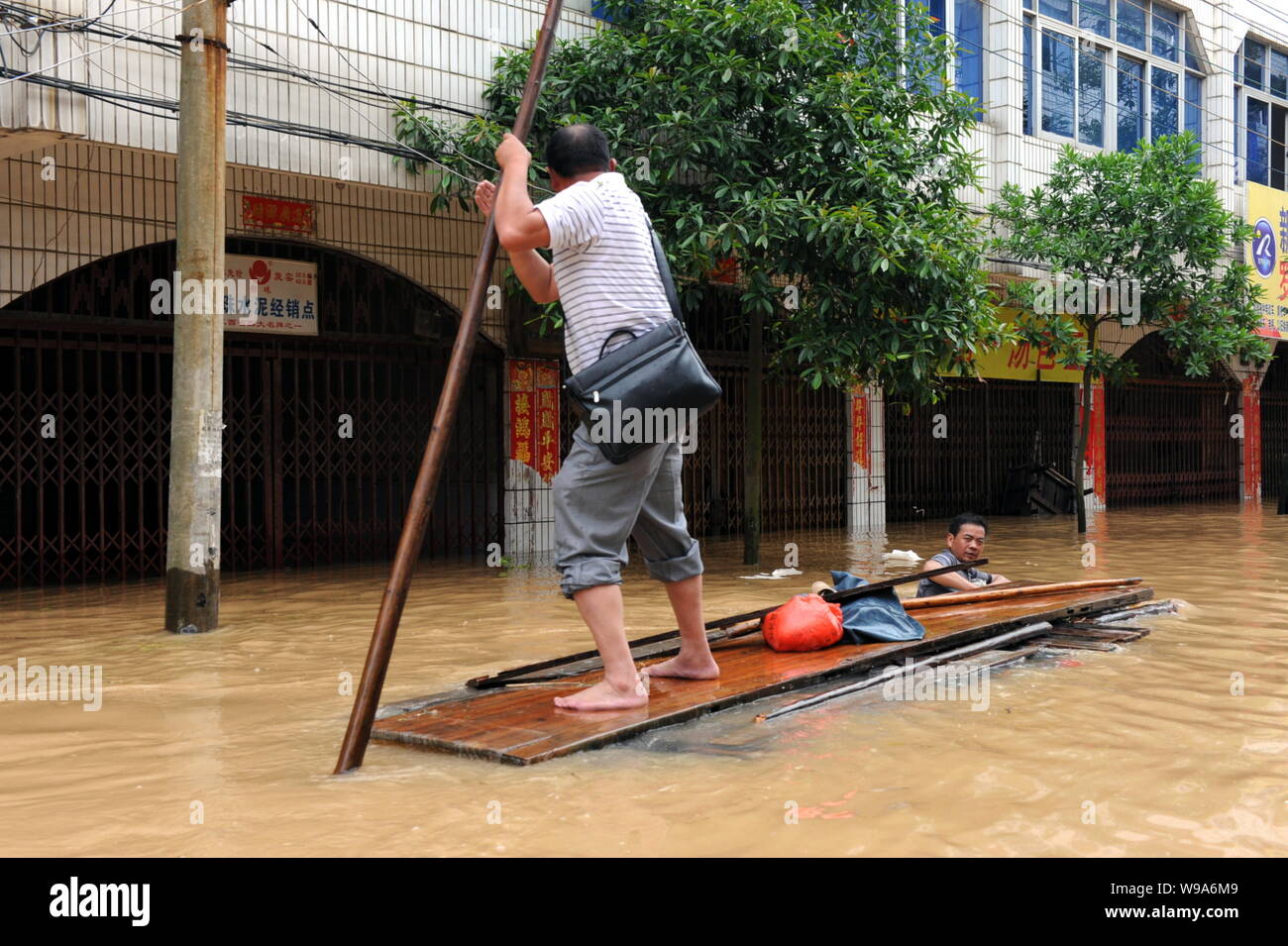 Local residents use a makeshift raft to evacuate from the flooded area ...