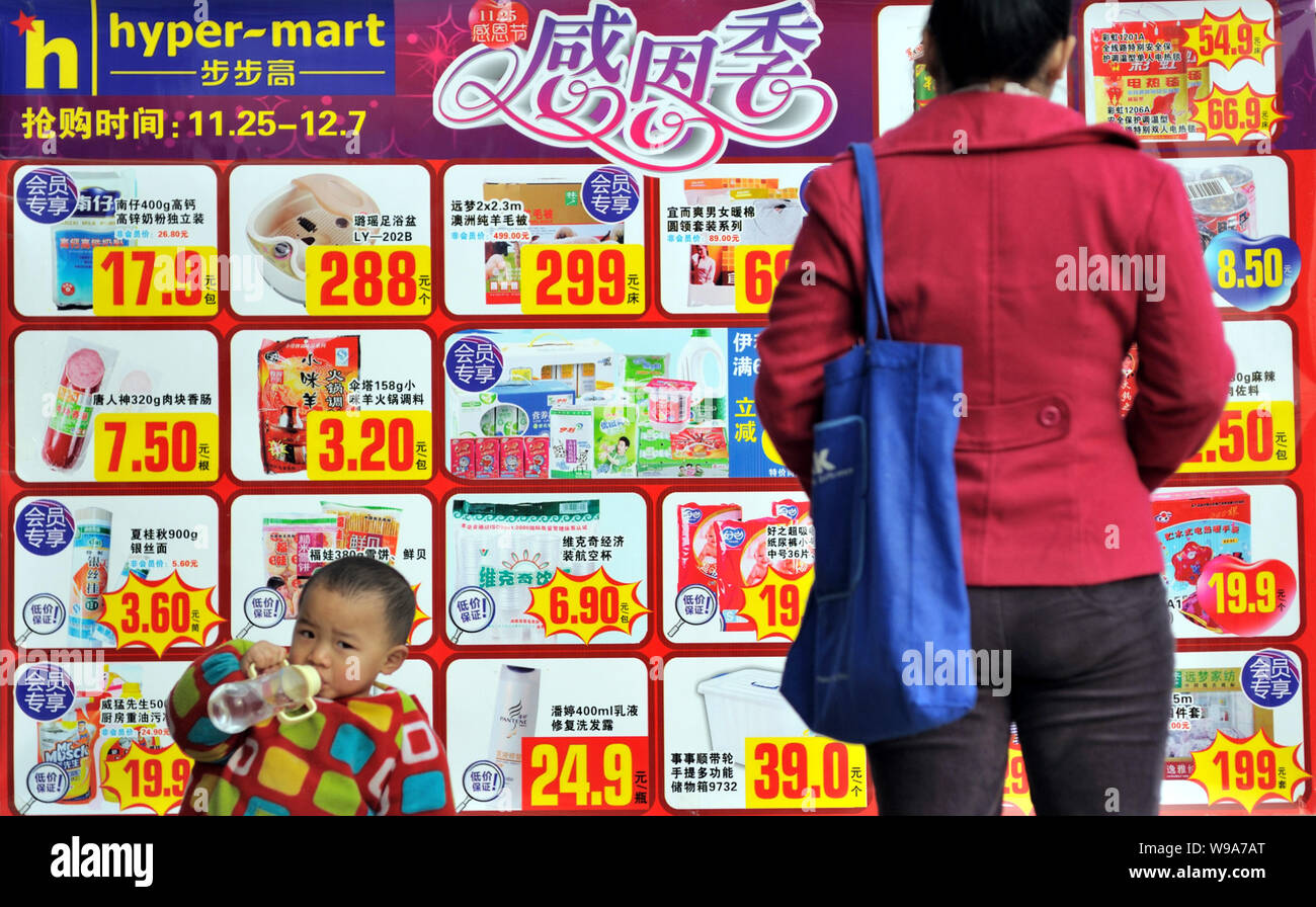 A Chinese customer looks at an advertising poster for products on sale ...