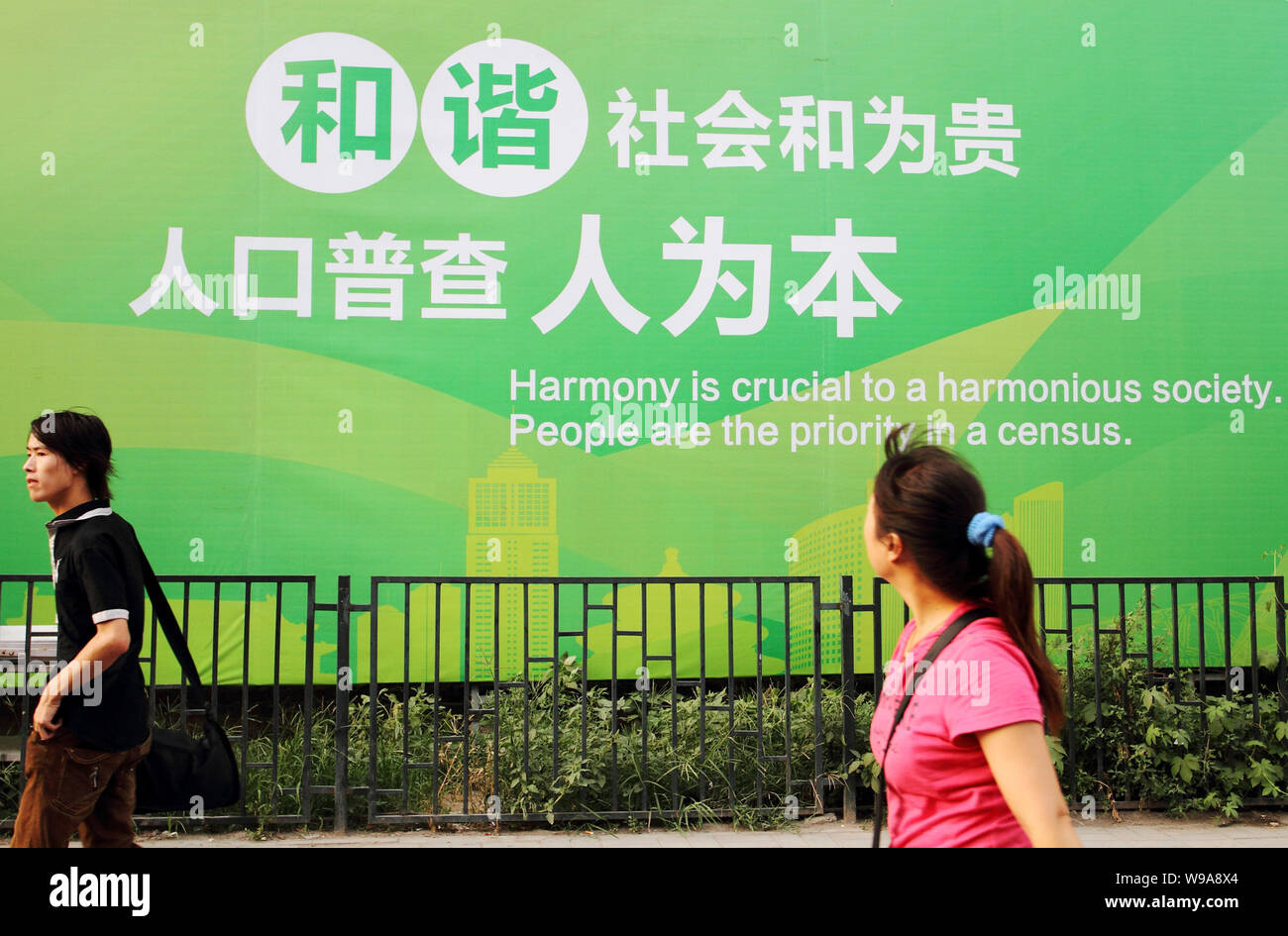 --FILE--Local Chinese residents walk past a propaganda billboard for ...