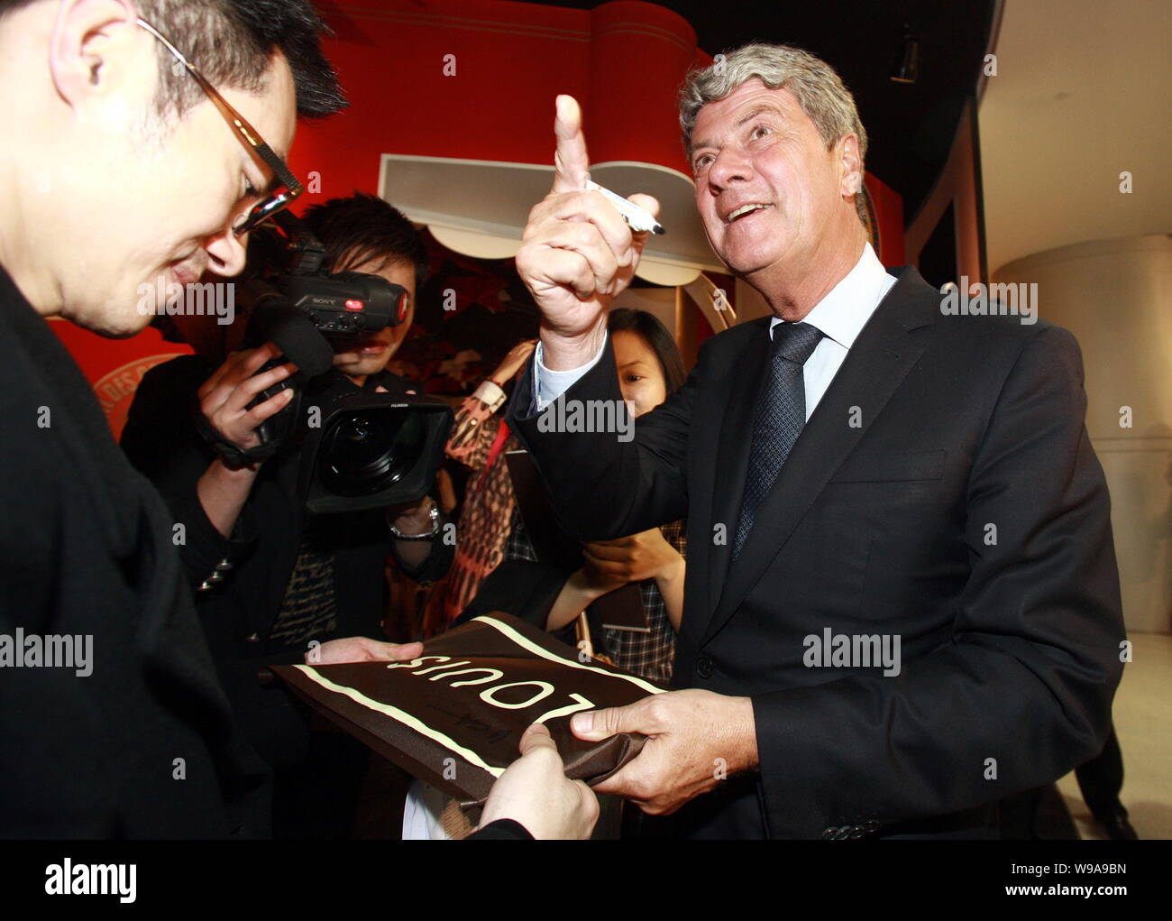 Yves Carcelle, Chairman and CEO of Louis Vuitton, signs for a visitor ...