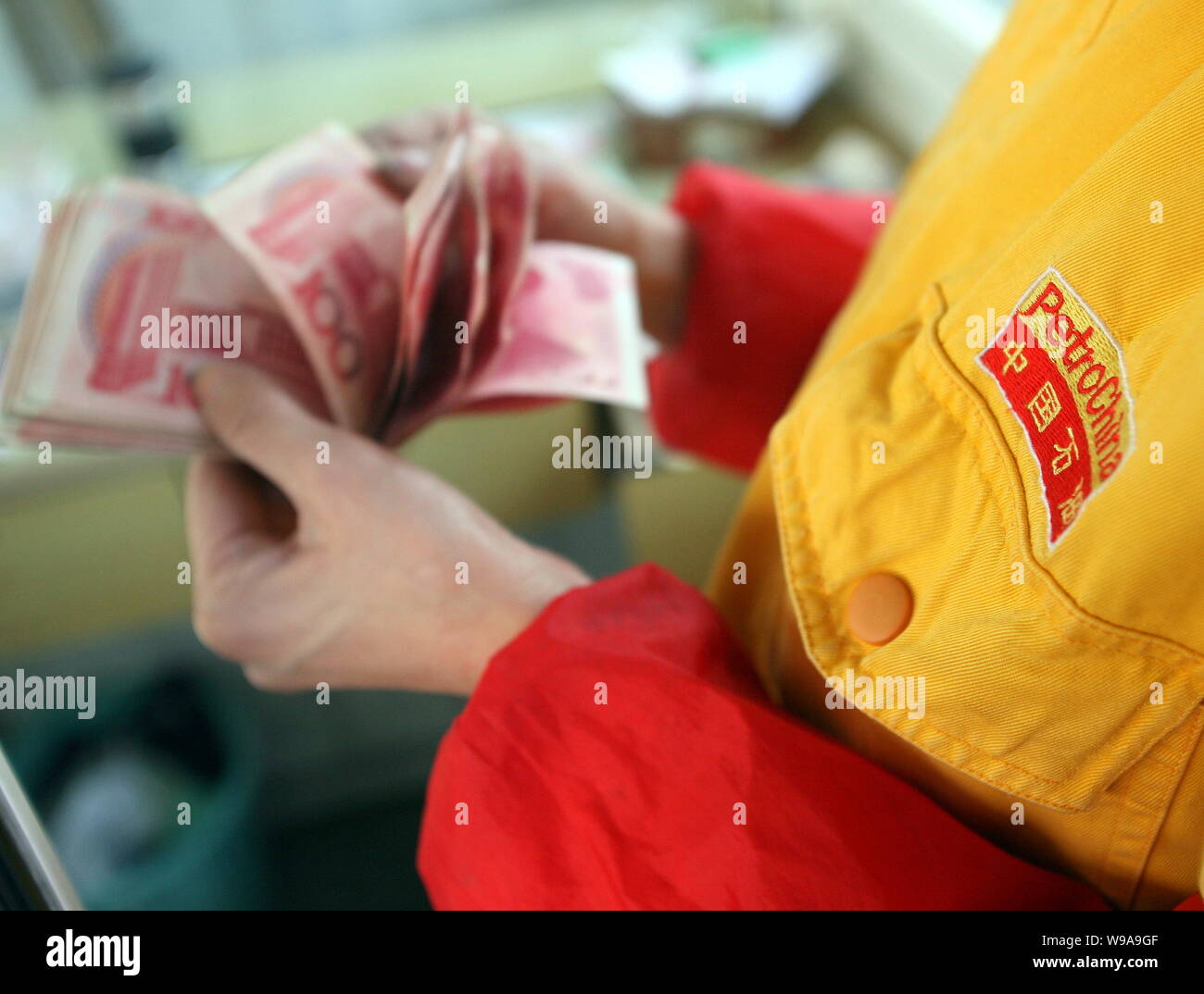 --FILE--A Chinese service station worker counts RMB (renminbi) yuan ...