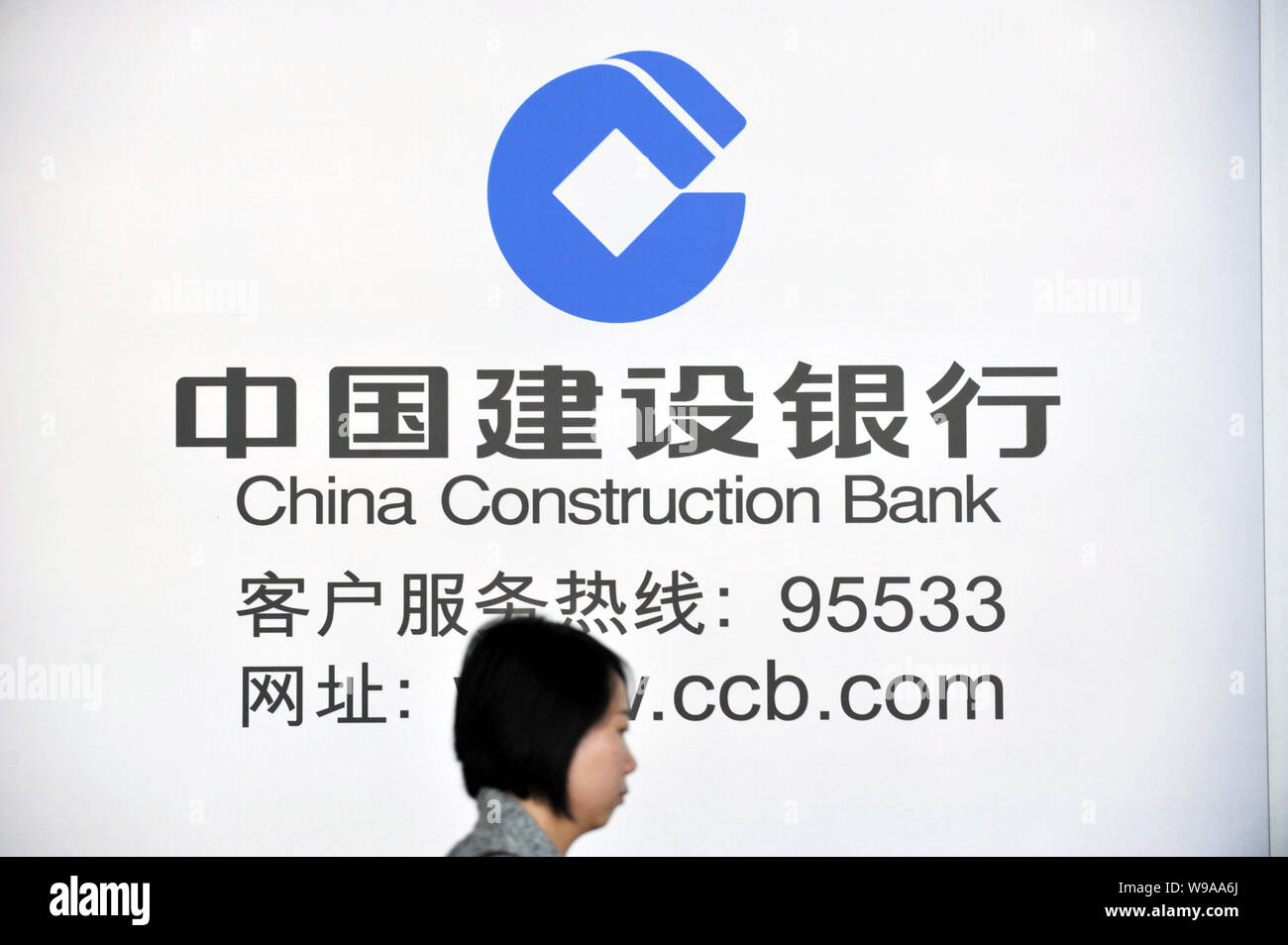 A passenger passes by an advertisement for China Construction Bank (CCB ...