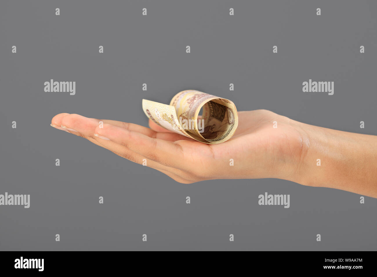 Close up of a person' hand holding roll of money Stock Photo - Alamy