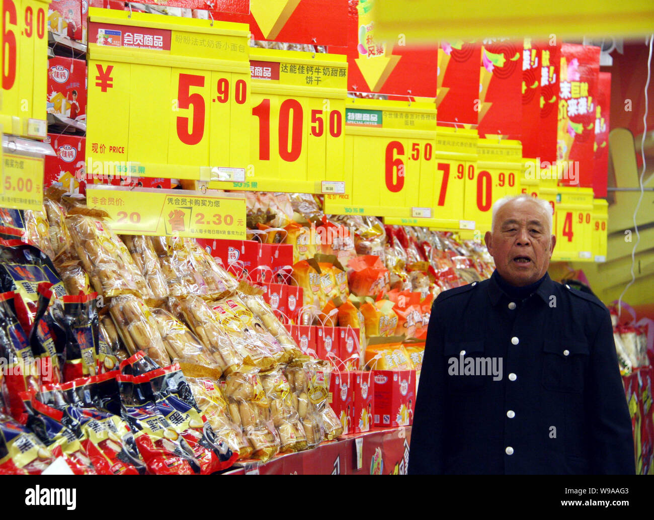 A Chinese customer walks past bags of snacks with price tags at a ...