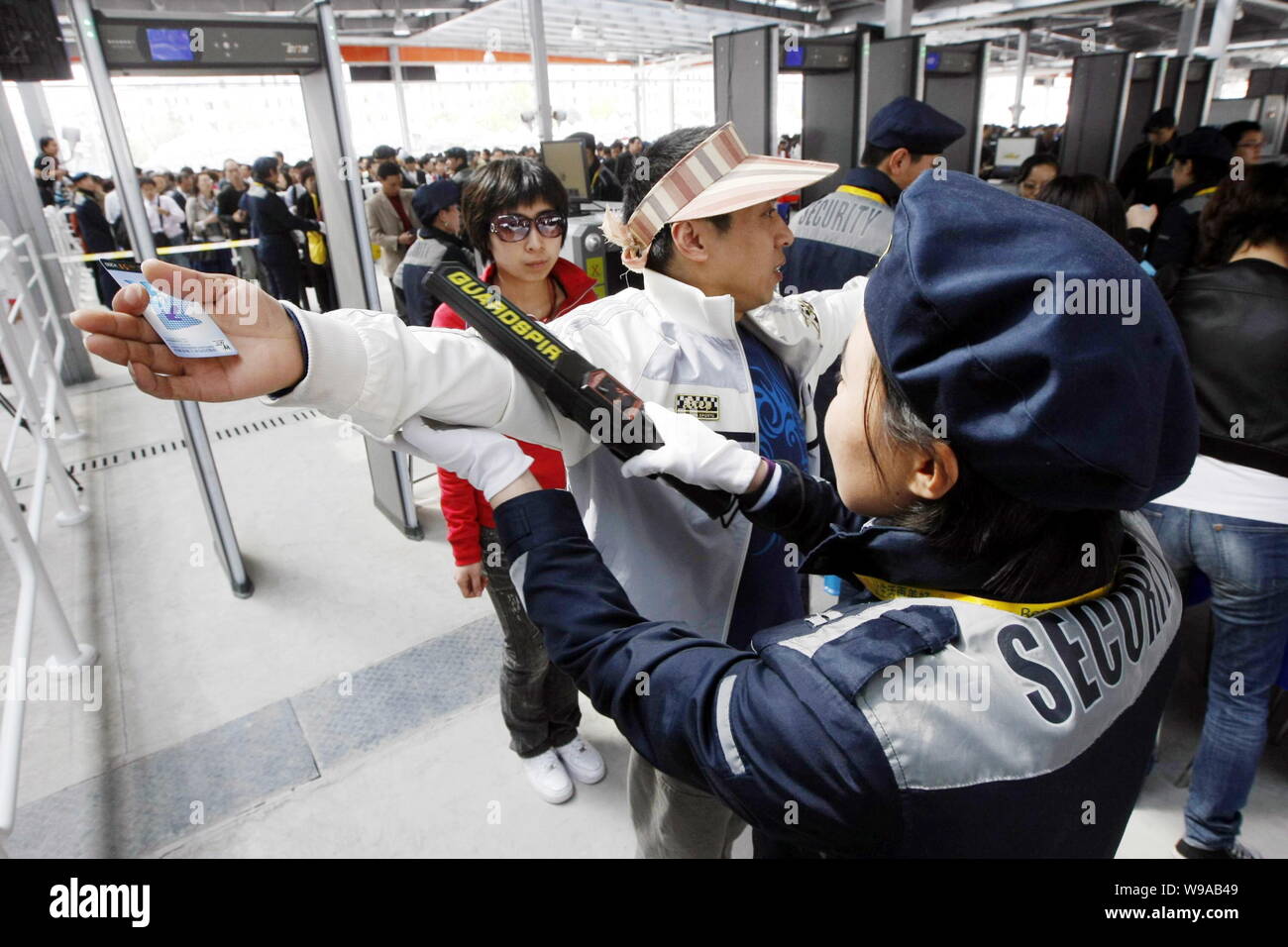 Chinese security staff scan visitors for security check at one entrance ...