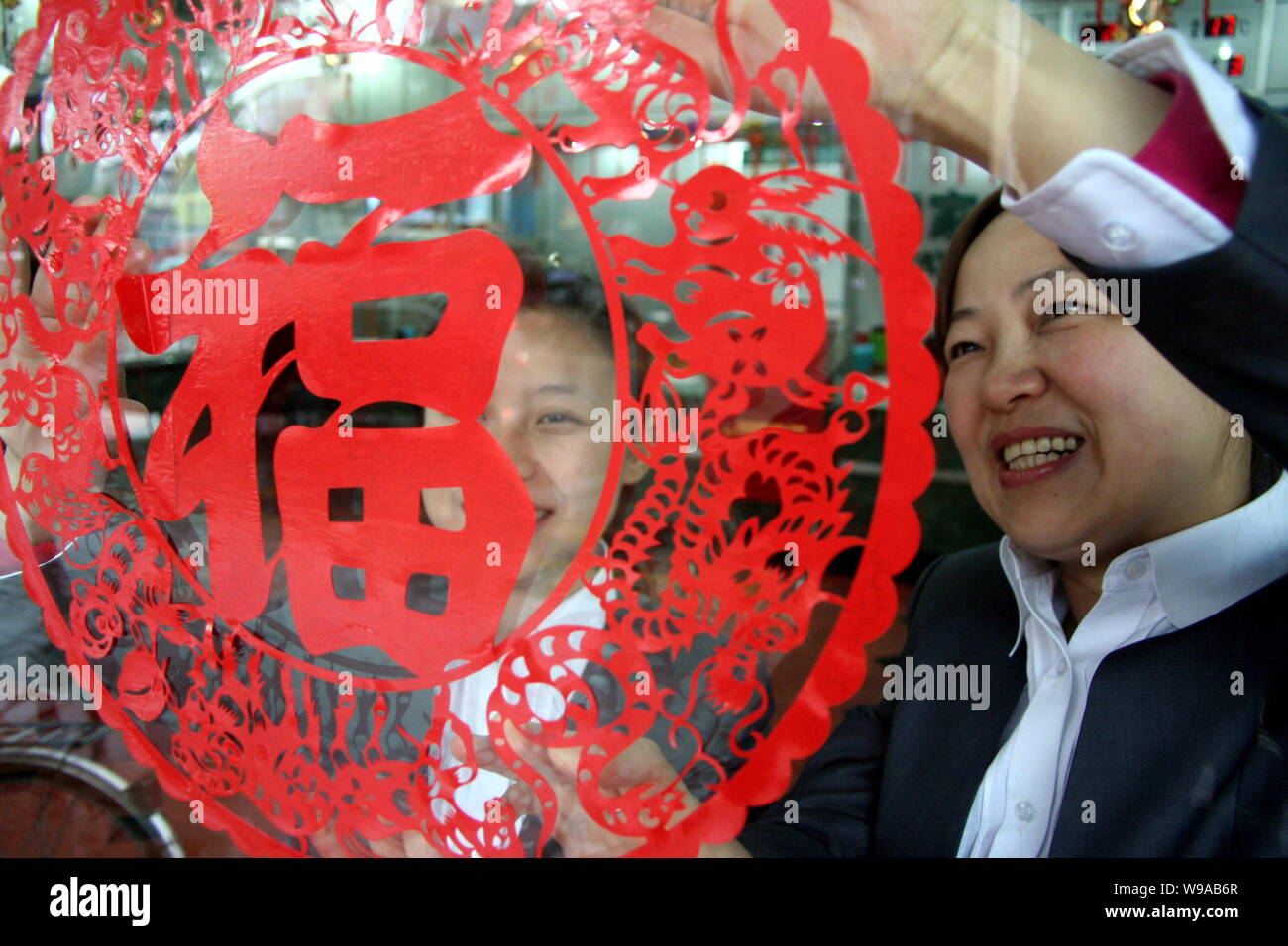 Chinese employees paste a paper-cut with the Chinese character Fu ...