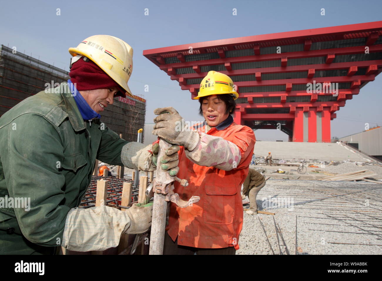 Chinese construction workers labor in front of the China Pavilion in ...