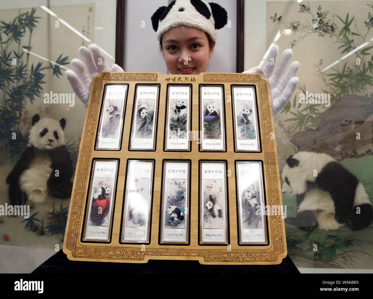 A Chinese showgirl displays a set of 10 panda-themed silver bars for ...