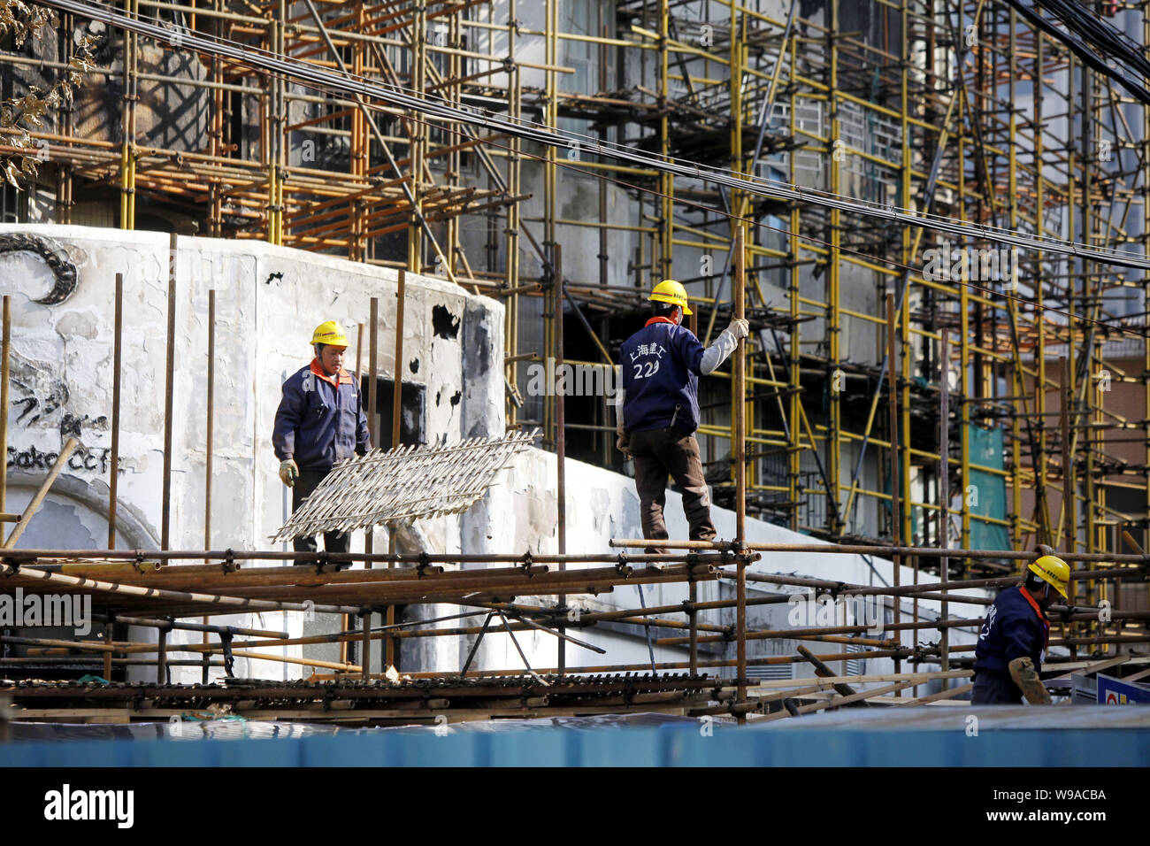 Chinese workers dismantle the scaffolding outside the fire-ravaged high ...