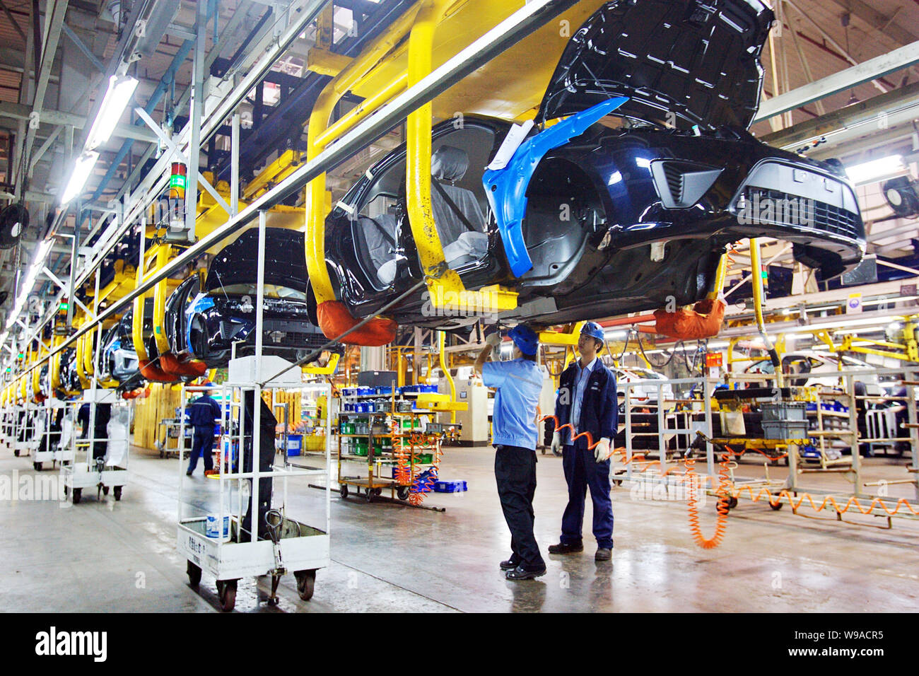 Chinese factory workers assemble Ford Focus cars on the assembly line ...