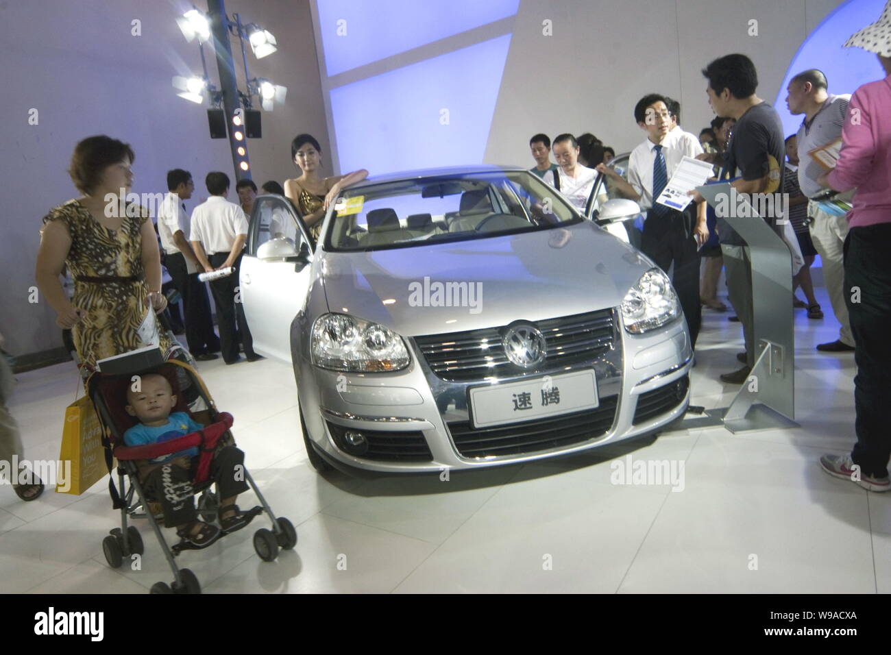 Chinese buyers look at a Volkswagen car during an auto show in Jinan ...