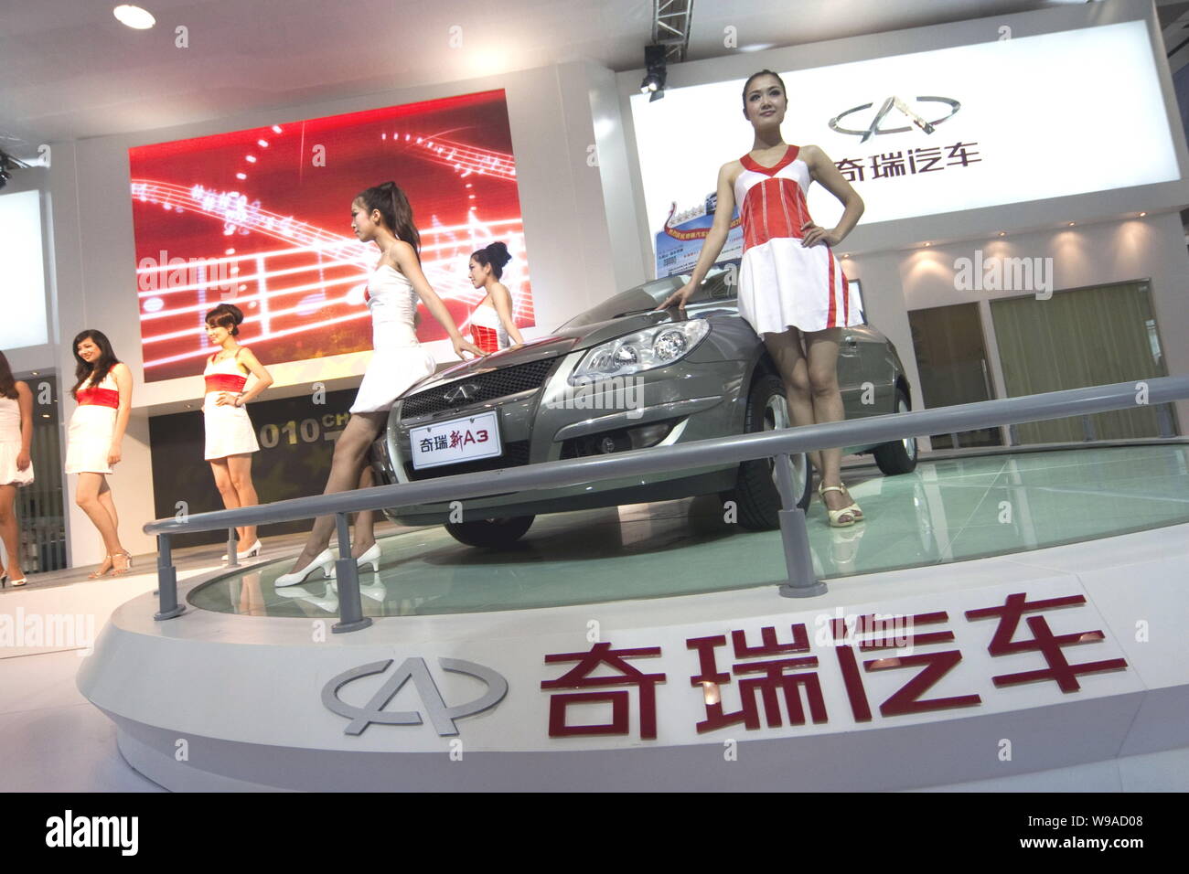 Chinese models pose beside a Chery A3 during an auto show in Jinan ...