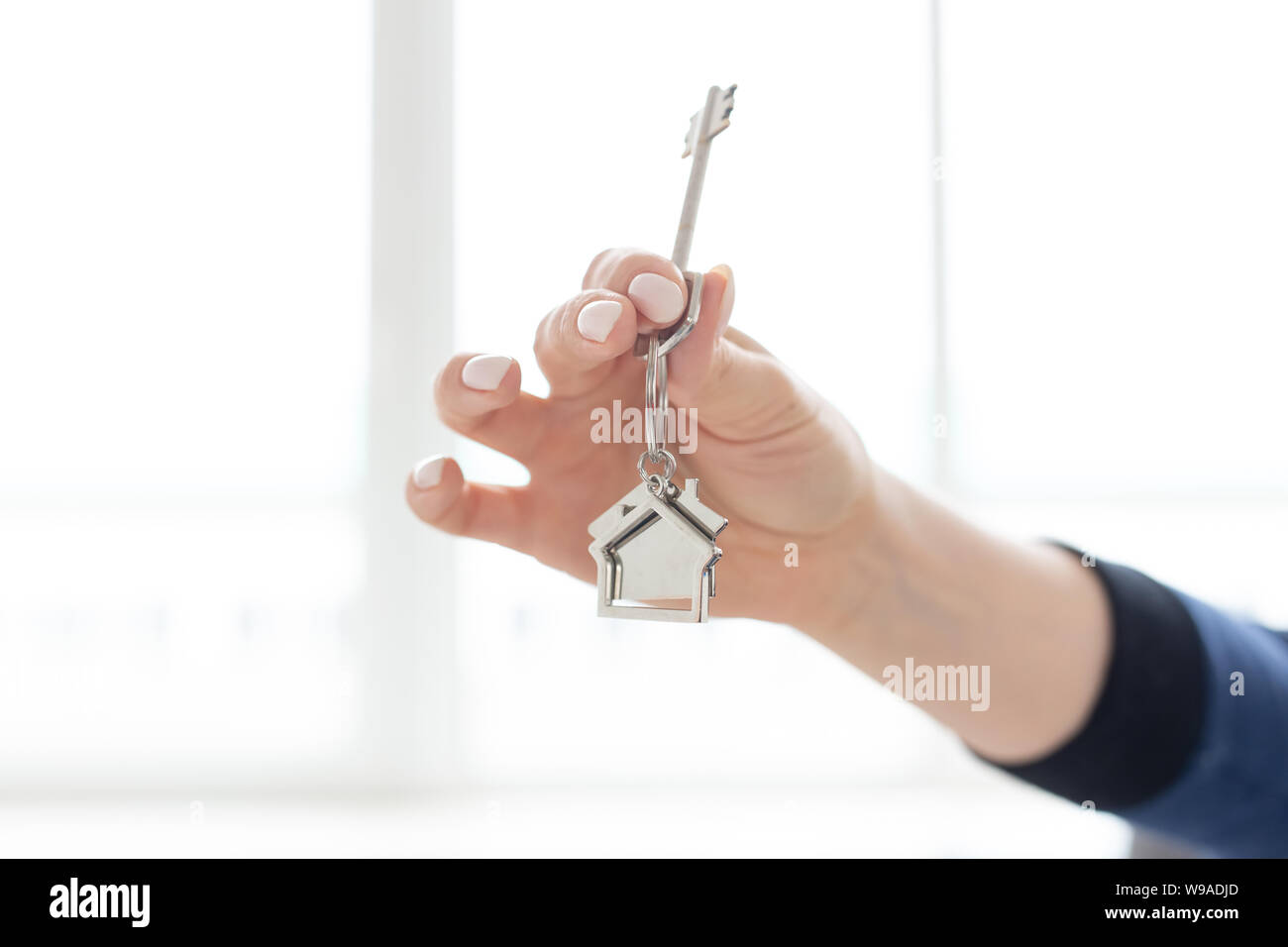 Real estate, moving and renting concept - Female hand holding keys with ...