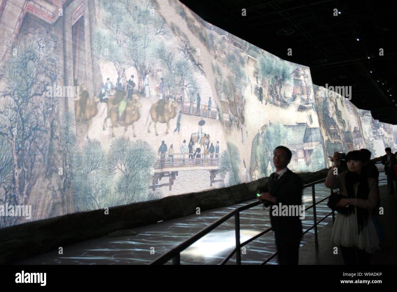 Visitors look at the projection of the painting, Riverside Scene at ...
