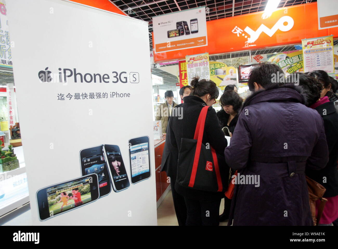 --FILE--Chinese customers stand next to an advertising poster for ...