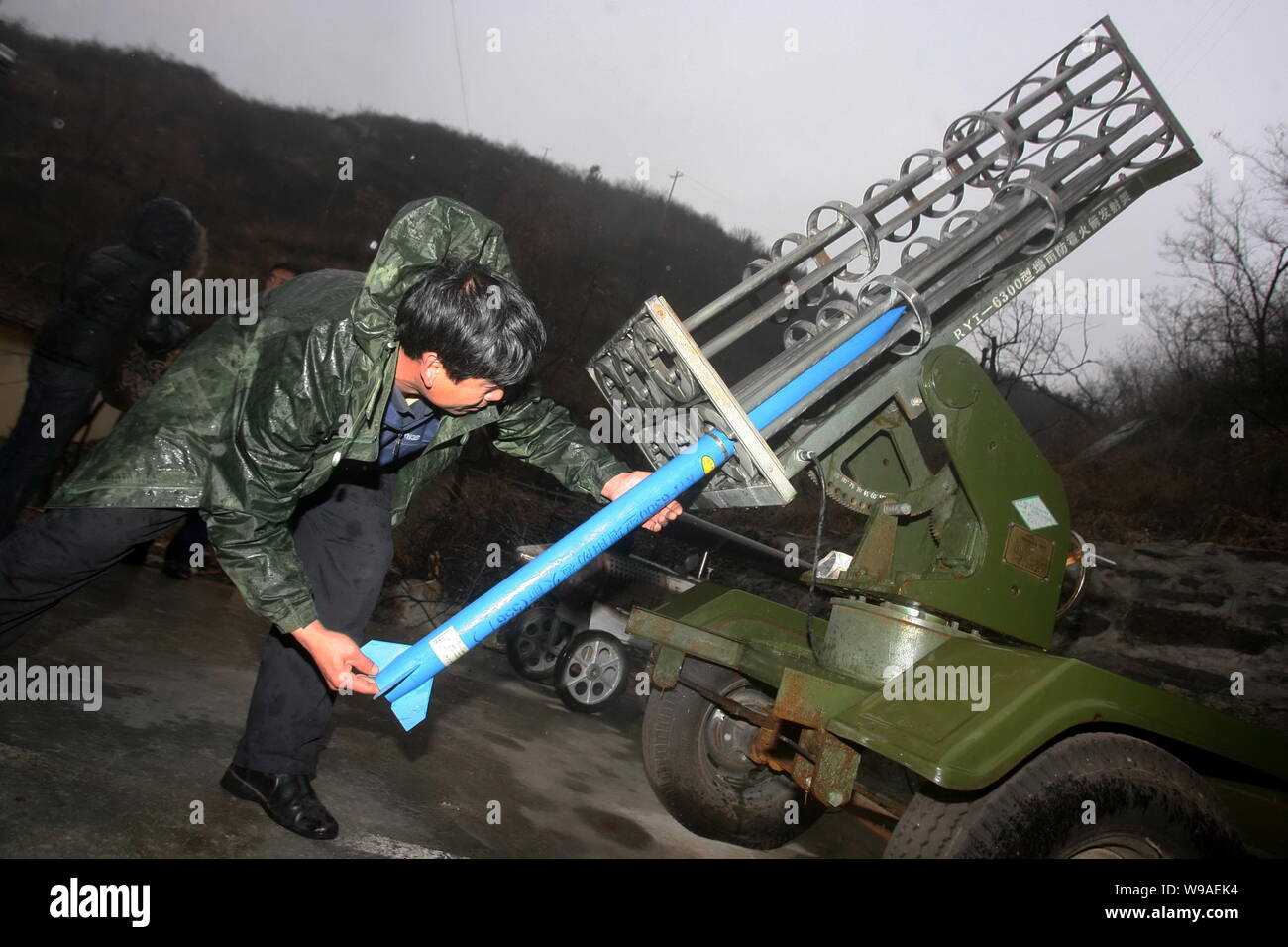 A Chinese meteorological department worker prepares to launch rockets ...