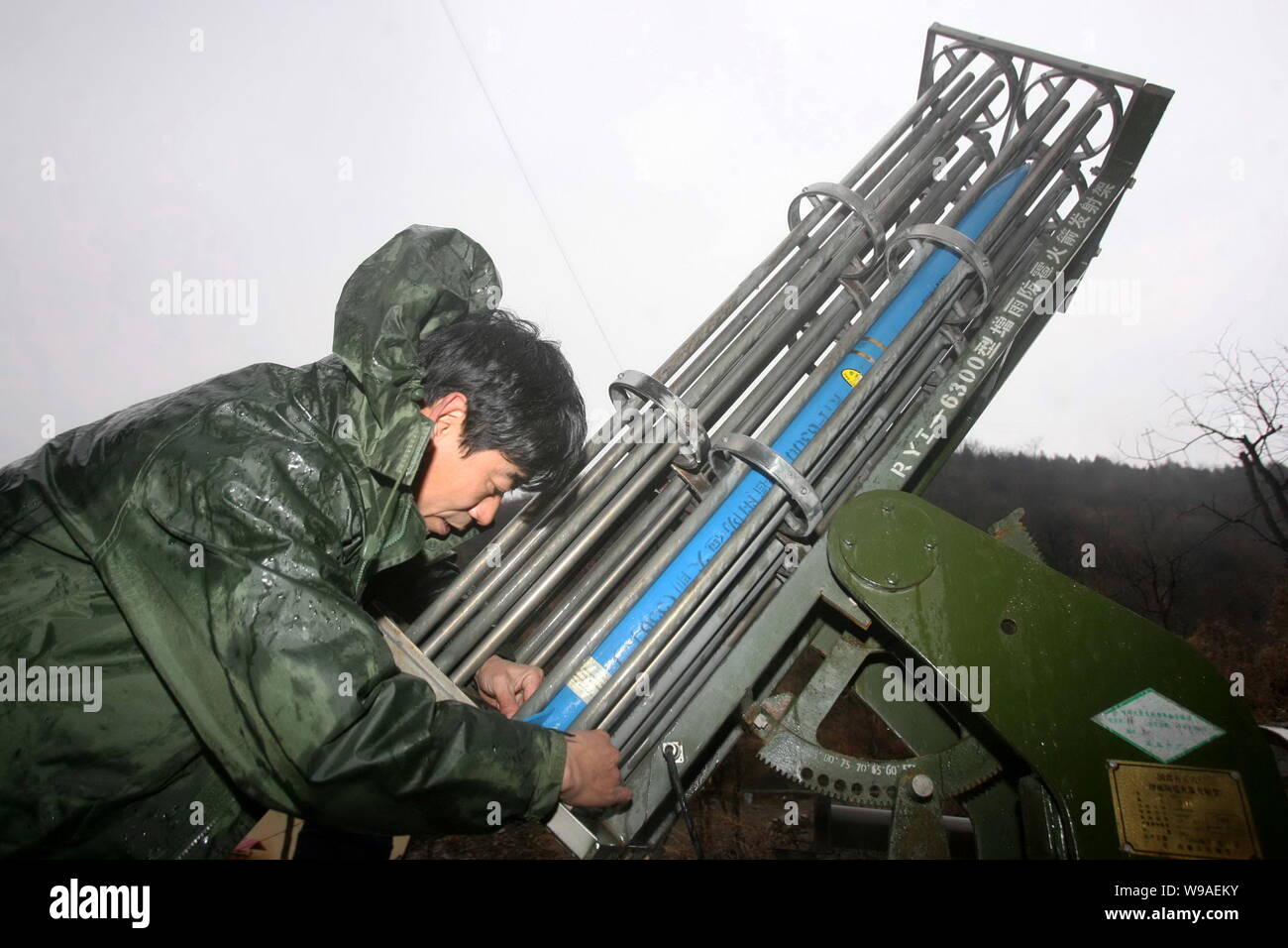 A Chinese meteorological department worker prepares to launch rockets ...