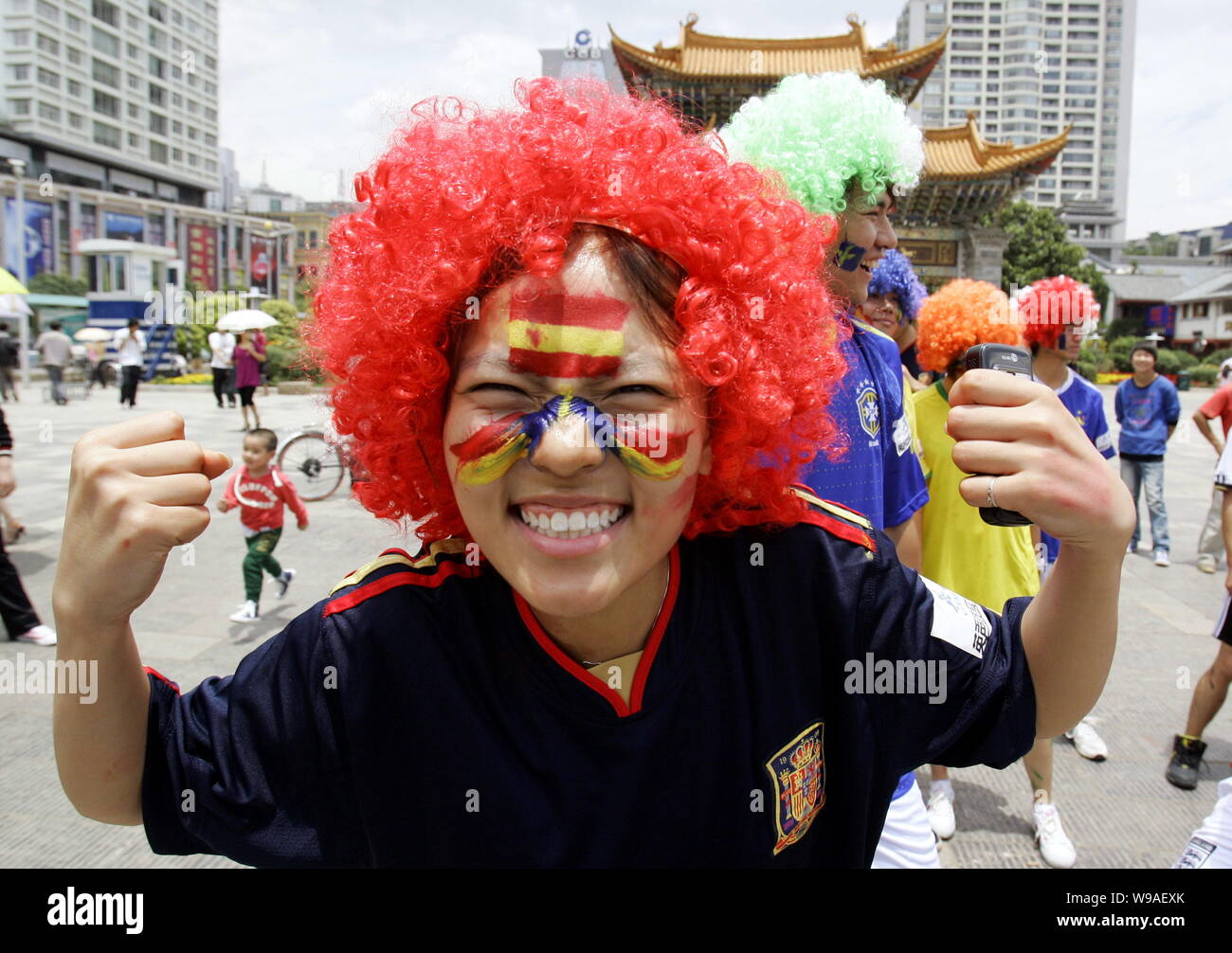 A Chinese soccer fan whose face is painted with the Spanish national ...