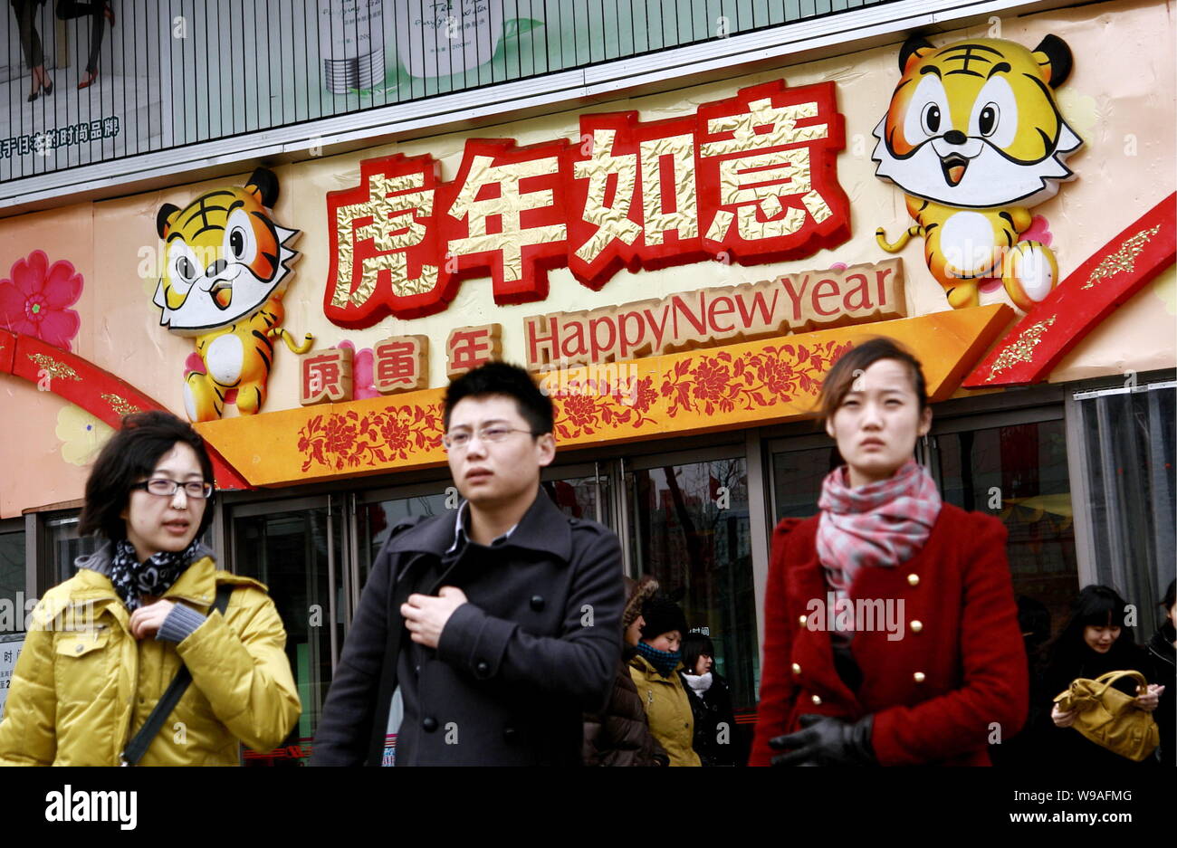 Chinese residents walk past a banner celebrating the upcoming Spring ...