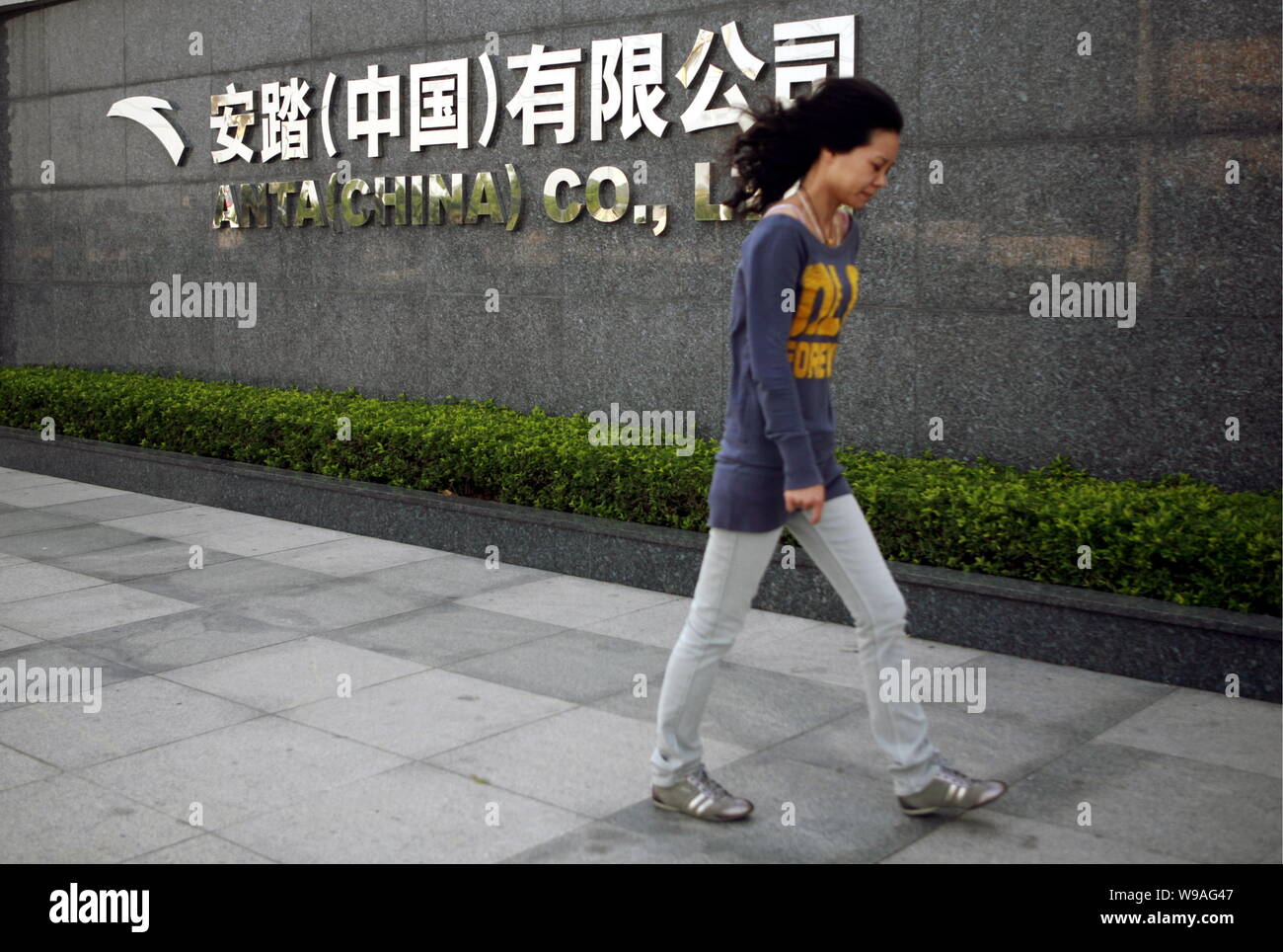 --File-- A young Chinese woman walks past the headquarters of Anta ...