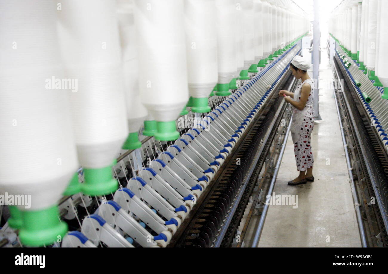 A female Chinese factory worker checks yarn on the spinning machine at ...