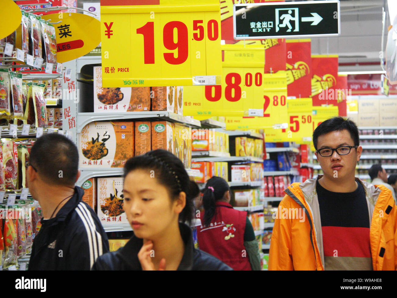 Chinese customers walk under price tags at a supermarket in Haian ...