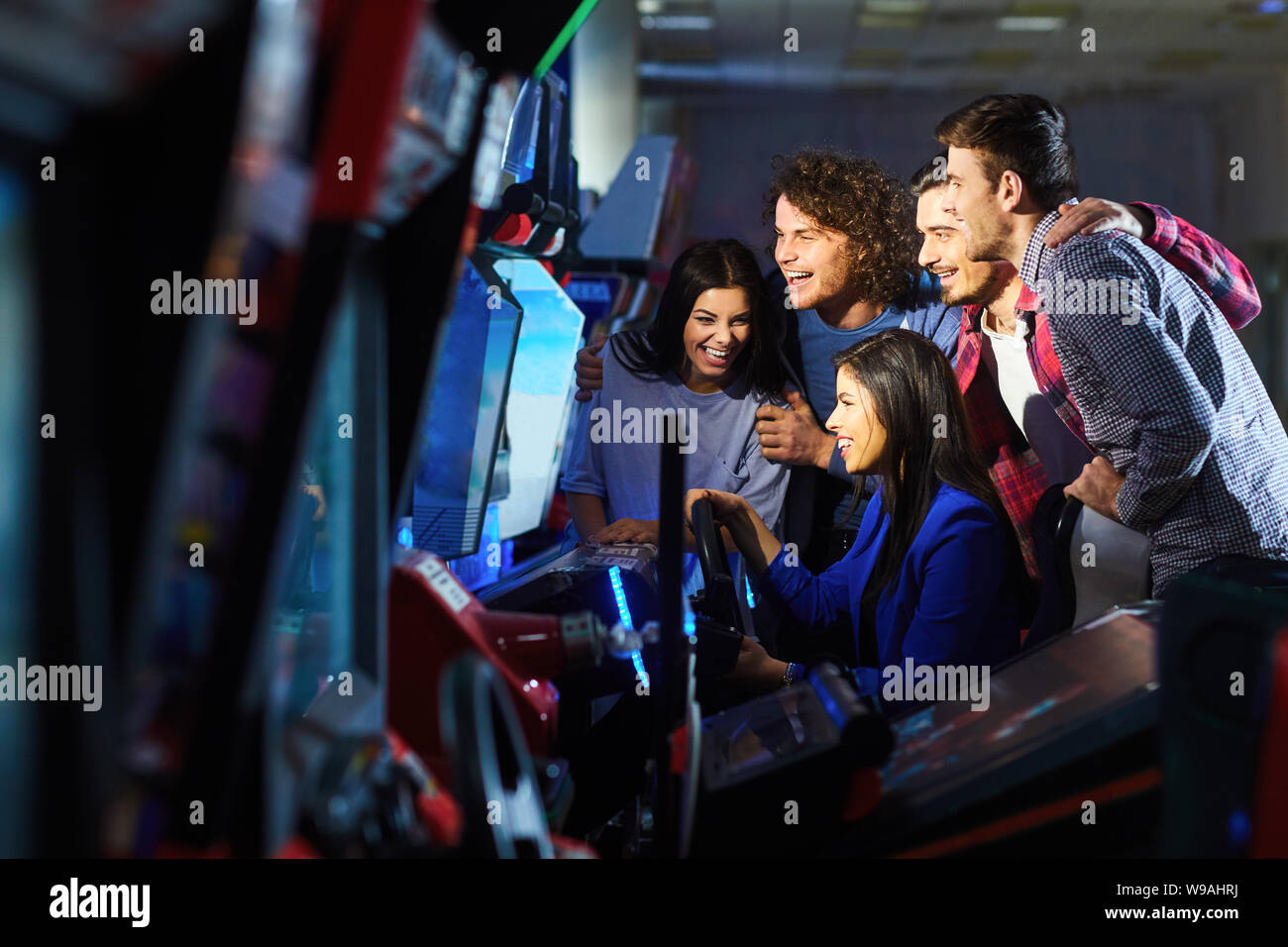 A group of friends playing arcade machine Stock Photo - Alamy