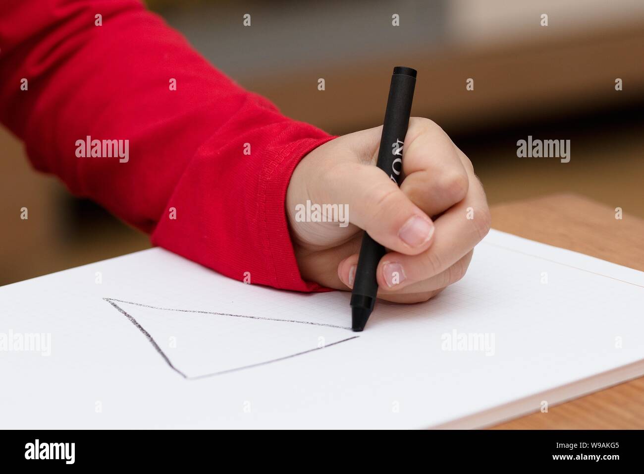 Left hand of a child drawing on white paper using black crayon Stock ...