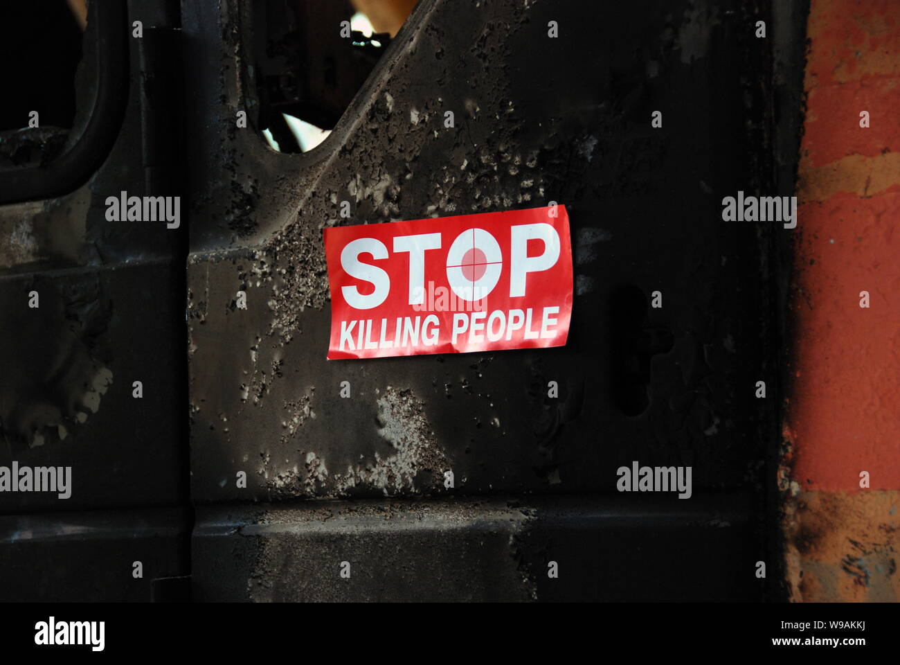A sign saying Stop Killing People is seen on a burnt-out excavator on ...