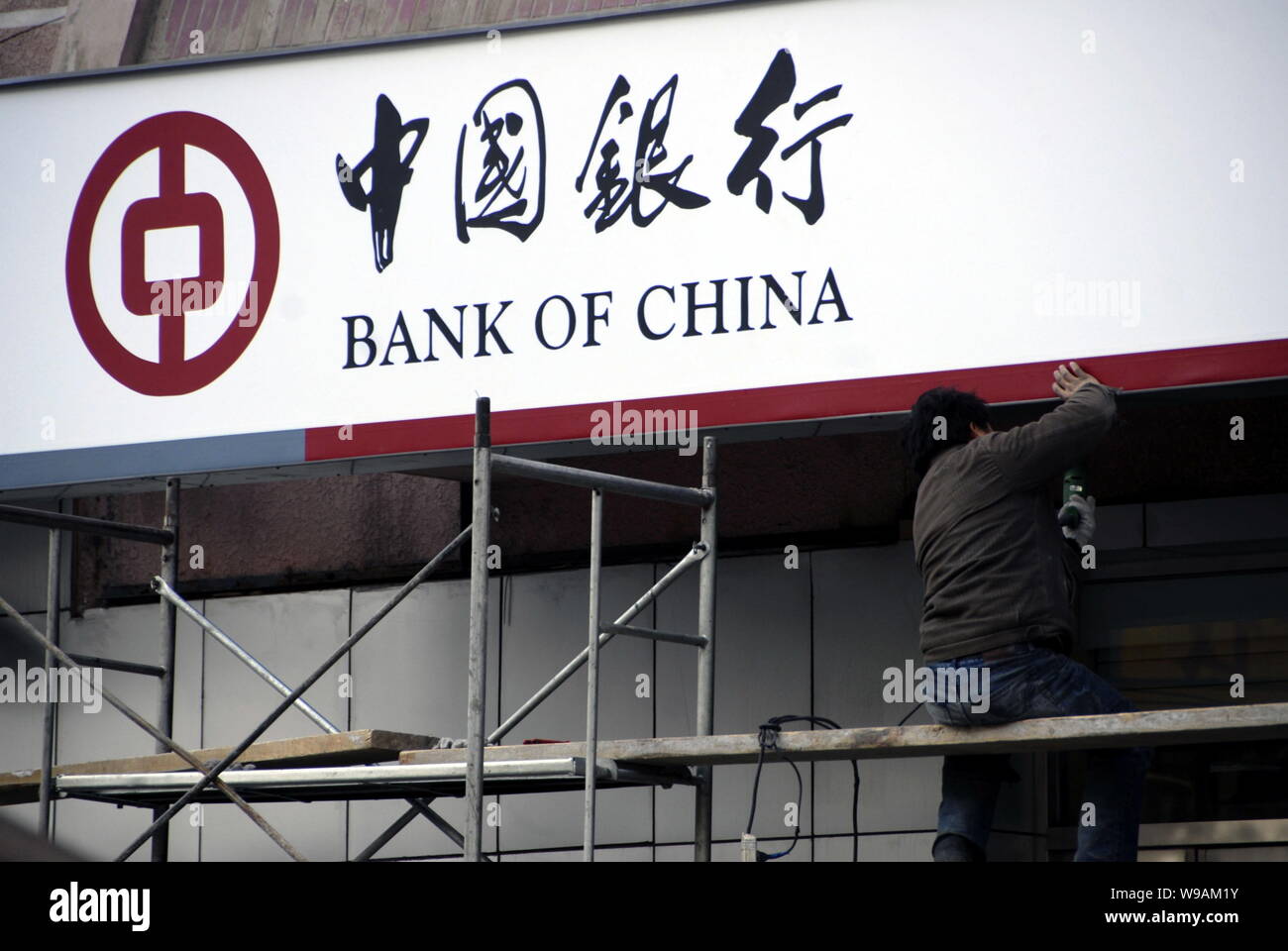 --FILE--A Chinese worker installs a signboard of Bank of China (BOC) at ...