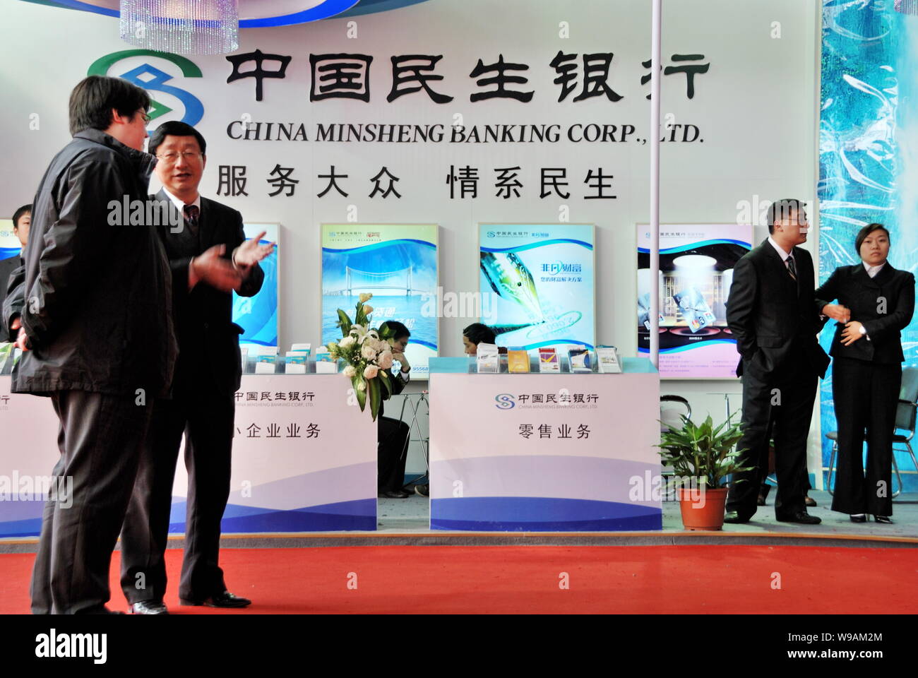 --FILE--Chinese employees talk with visitors at the stand of China ...