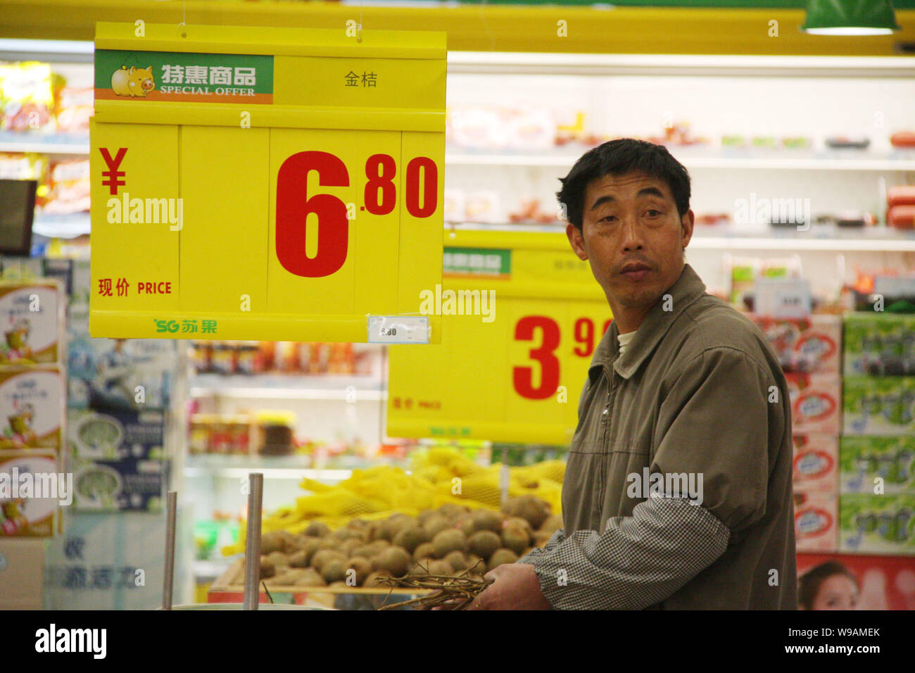 A Chinese man stands next to price tags at a supermarket in Nantong ...