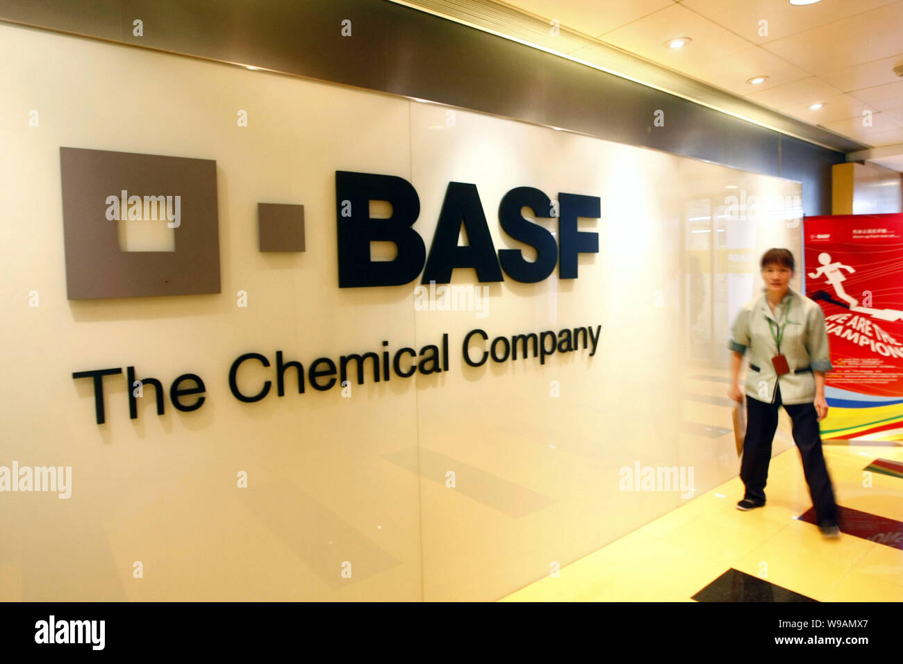 --FILE--A Chinese cleaner stands next to the logo of BASF in the ...