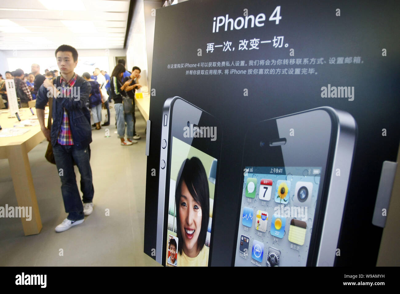 Chinese buyers walk past an advertising poster for the iPhone 4 ...