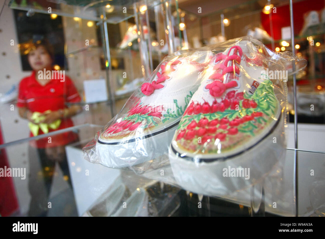 A Chinese staff walks past a pair of sneakers in a flagship shoe store ...
