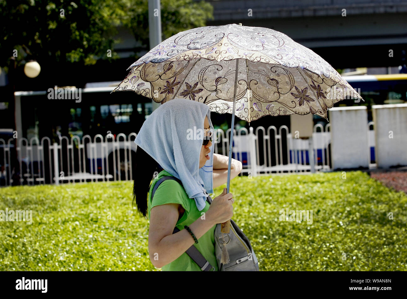 A Chinese woman covers her head with a towel and shields herself with ...